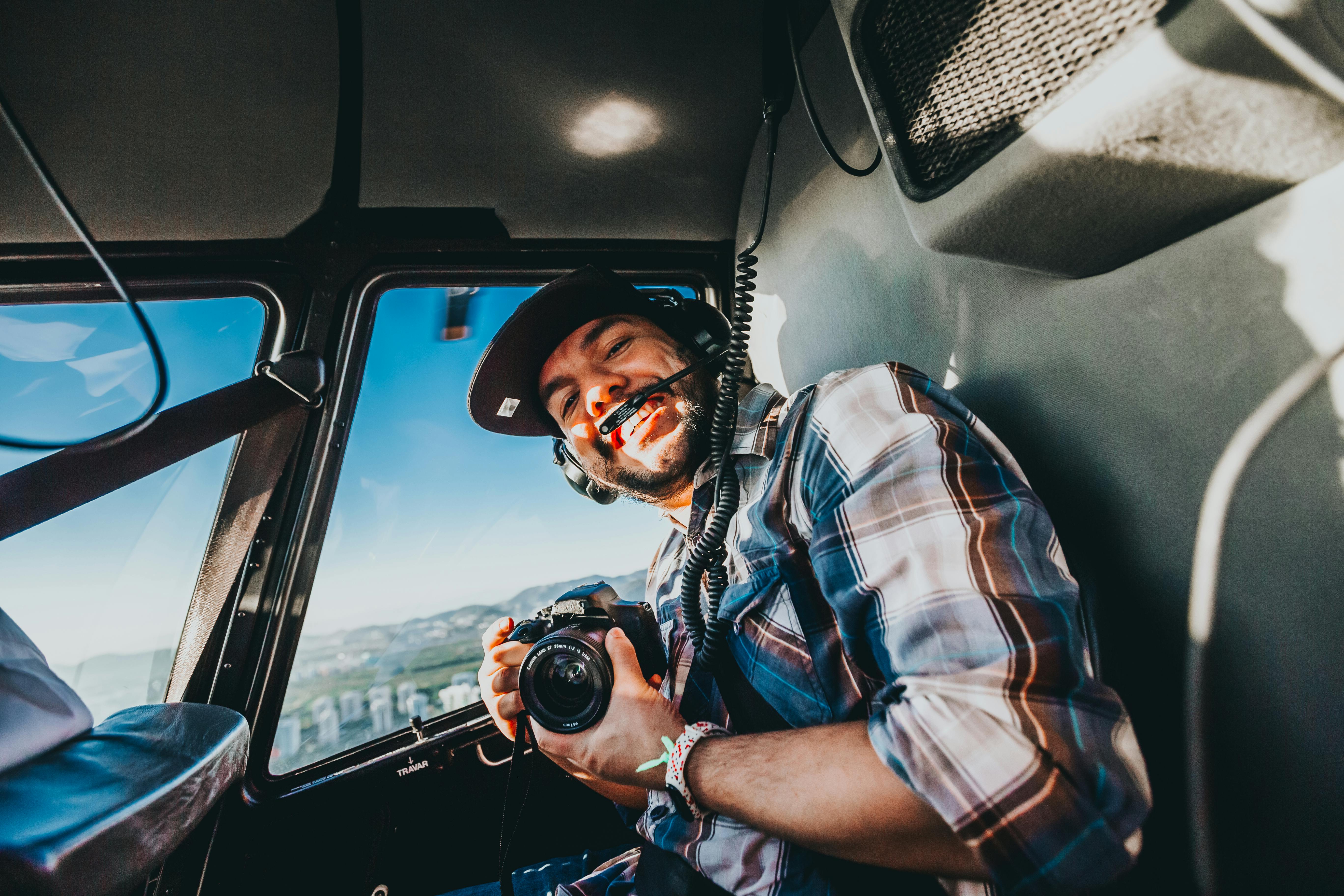 Smiling Man Holding Dslr Camera Inside a Plane · Free Stock Photo