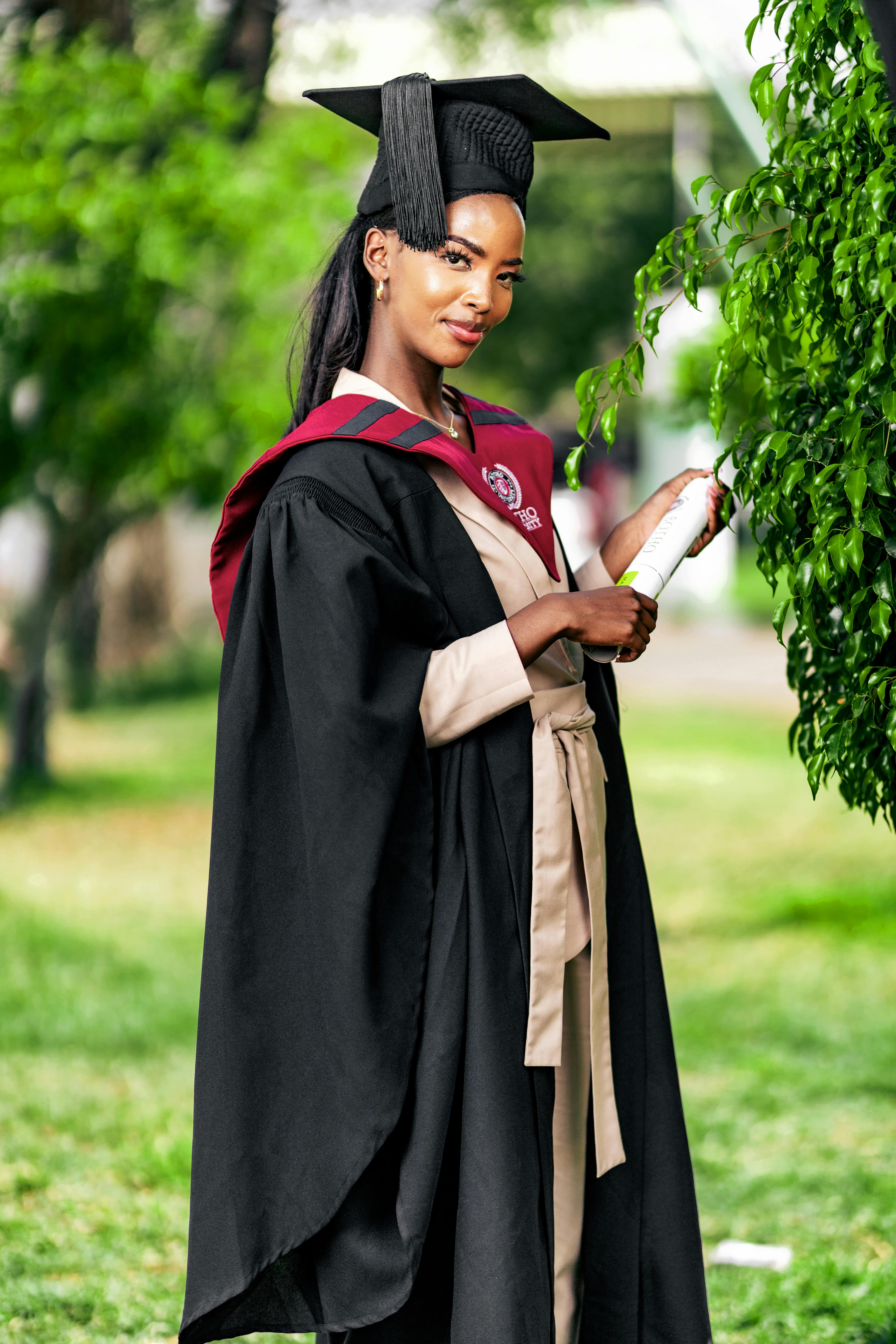 Joyful Graduate Posing Outdoors in Cap and Gown · Free Stock Photo