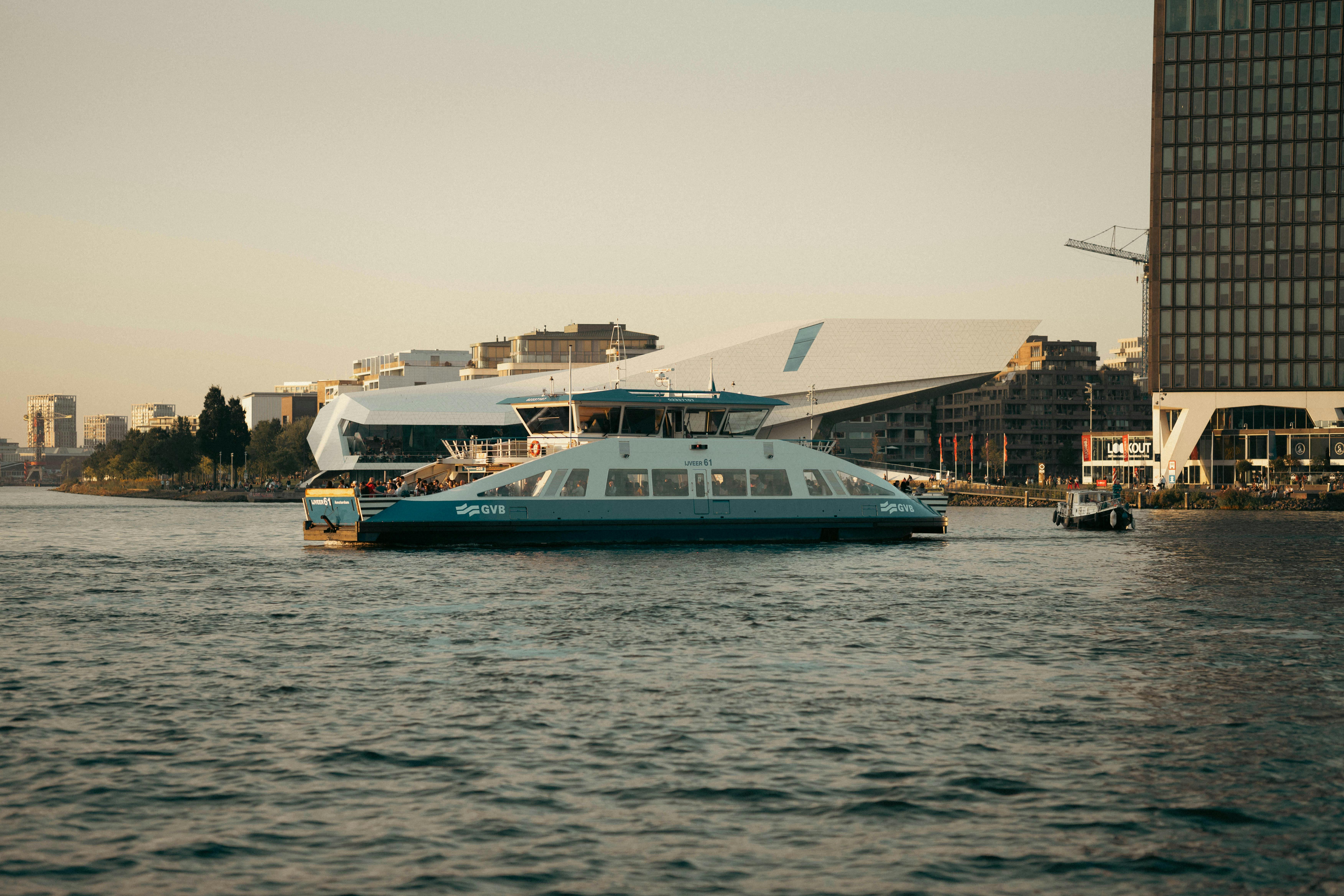 Modern ferry on Amsterdam waterfront at sunset · Free Stock Photo