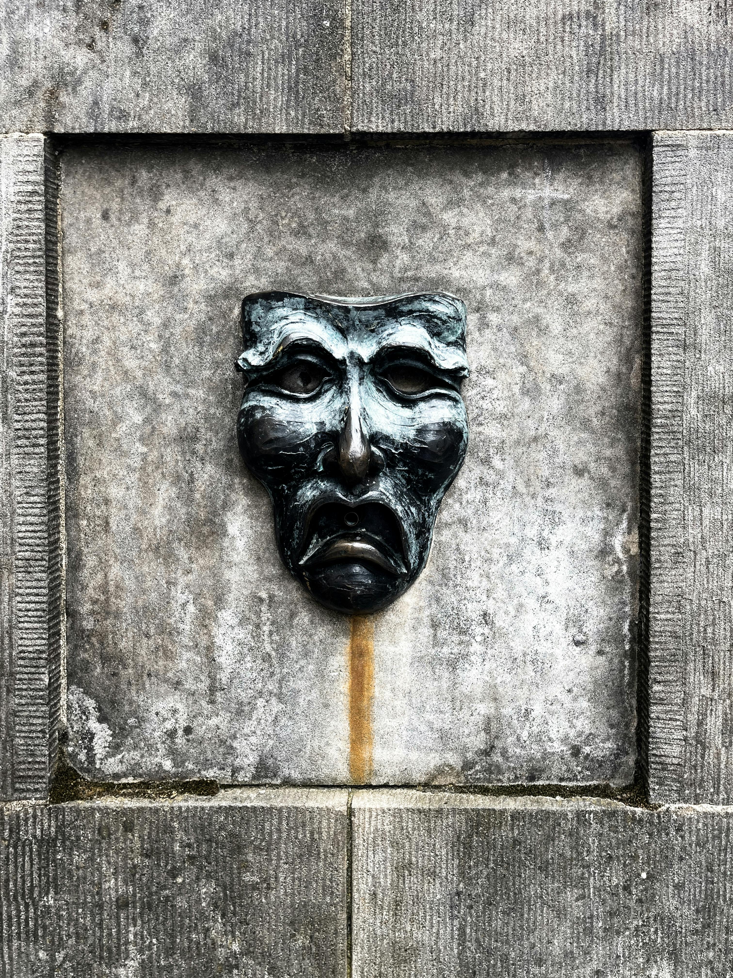 Dramatic Stone Mask Sculpture on Wall · Free Stock Photo