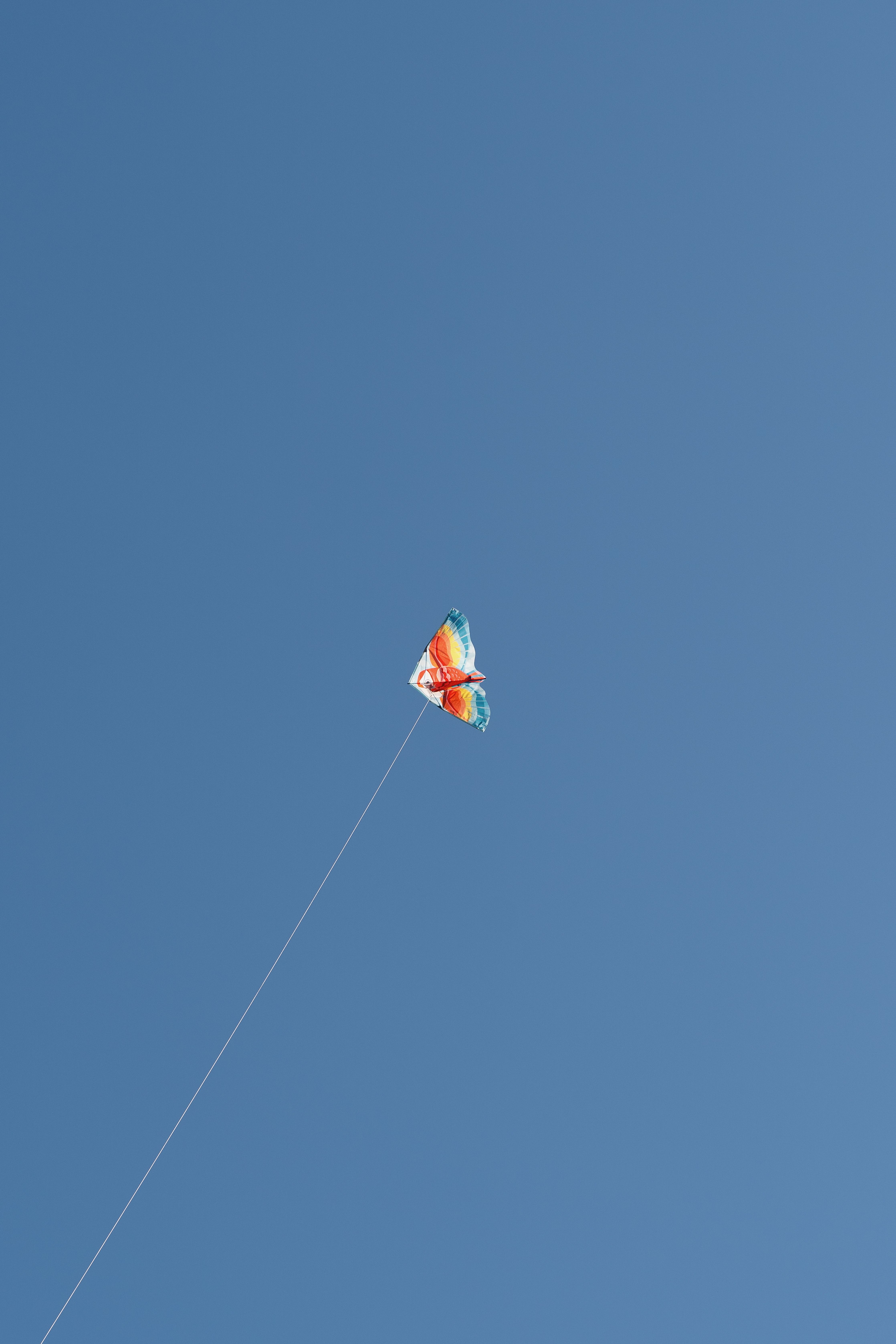 Colorful Kite Flying Against Clear Blue Sky · Free Stock Photo
