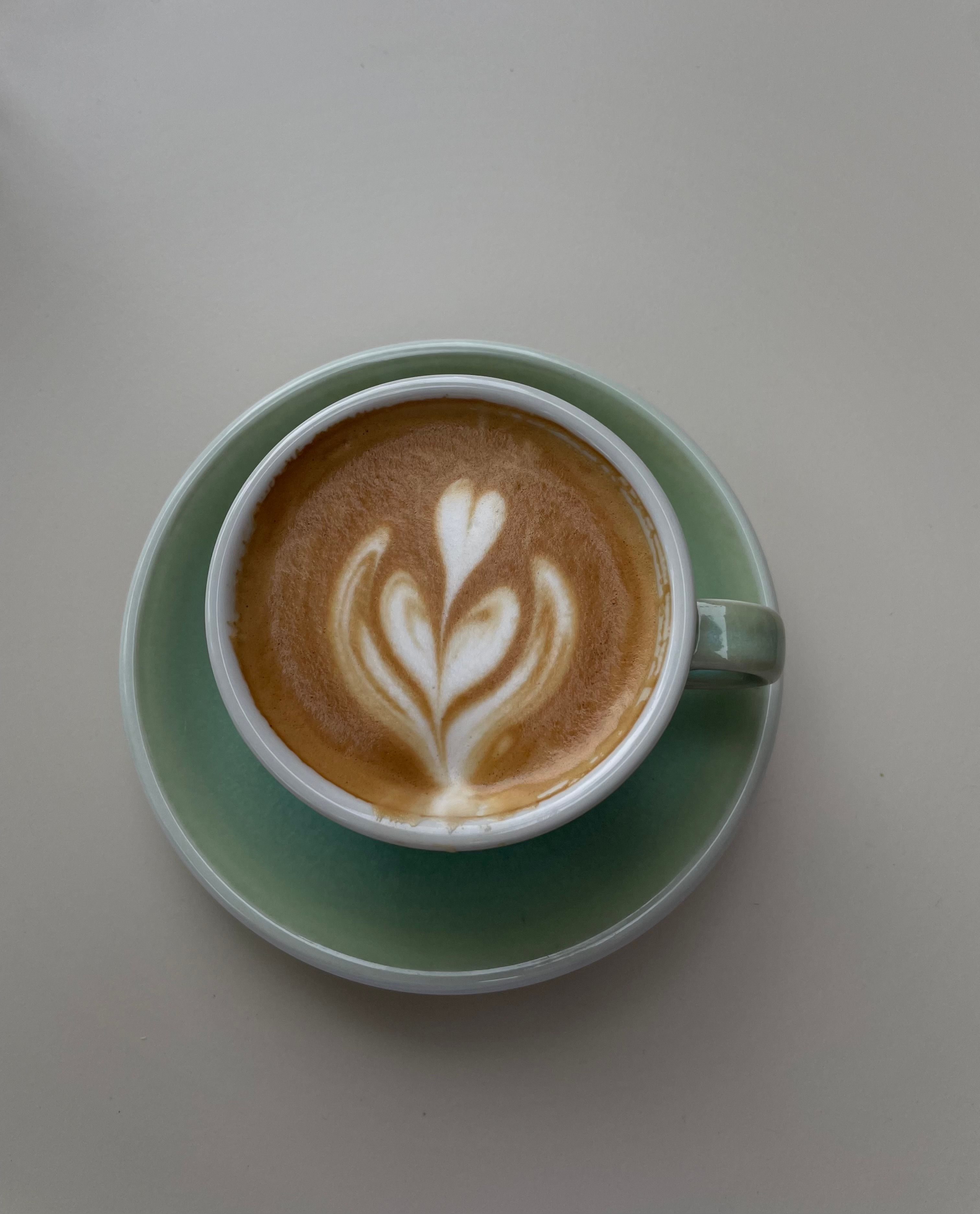 Elegant Latte Art in Green Cup on Table · Free Stock Photo