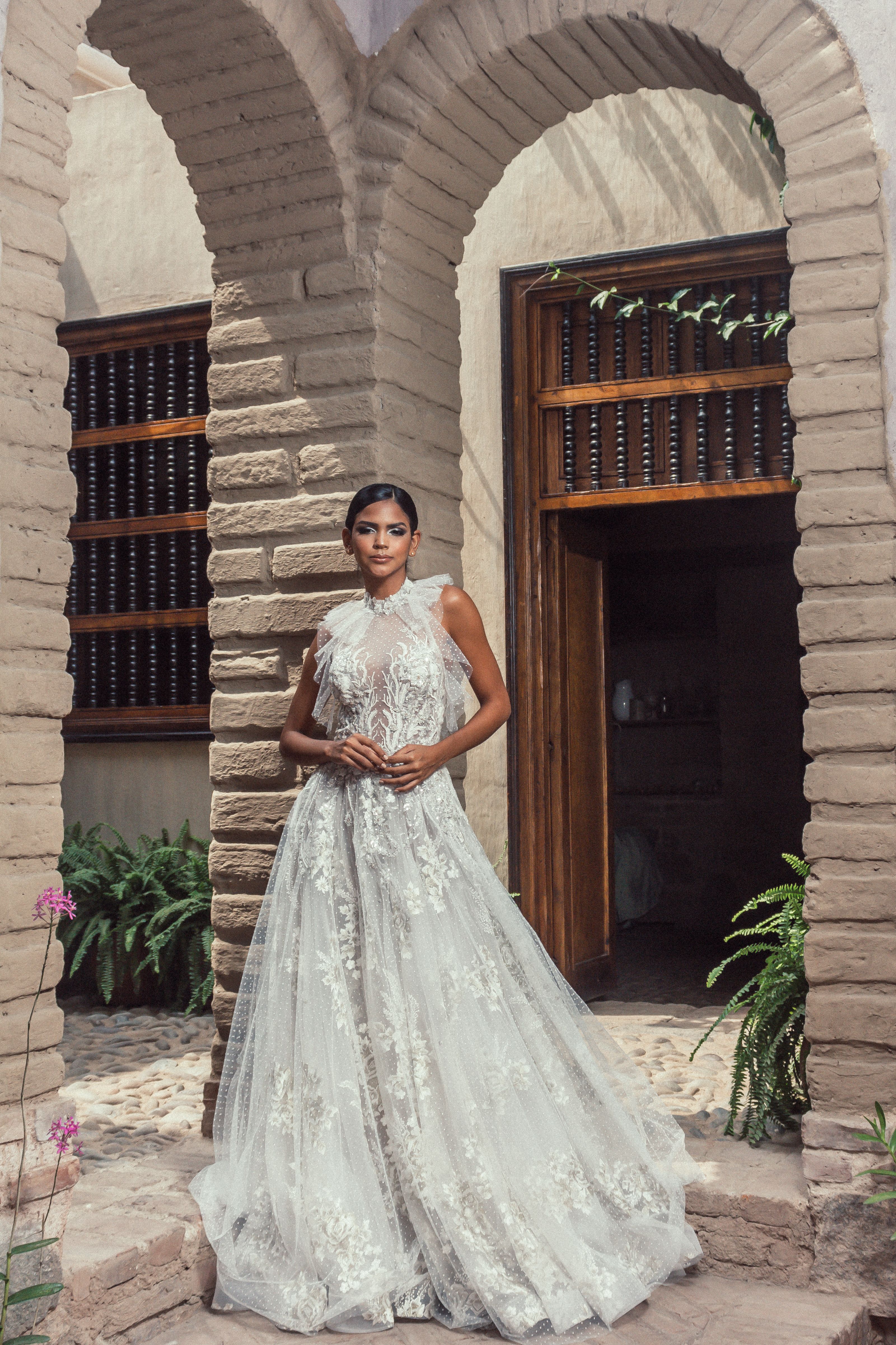 Elegant Bride in Lace Gown Under Rustic Arches · Free Stock Photo