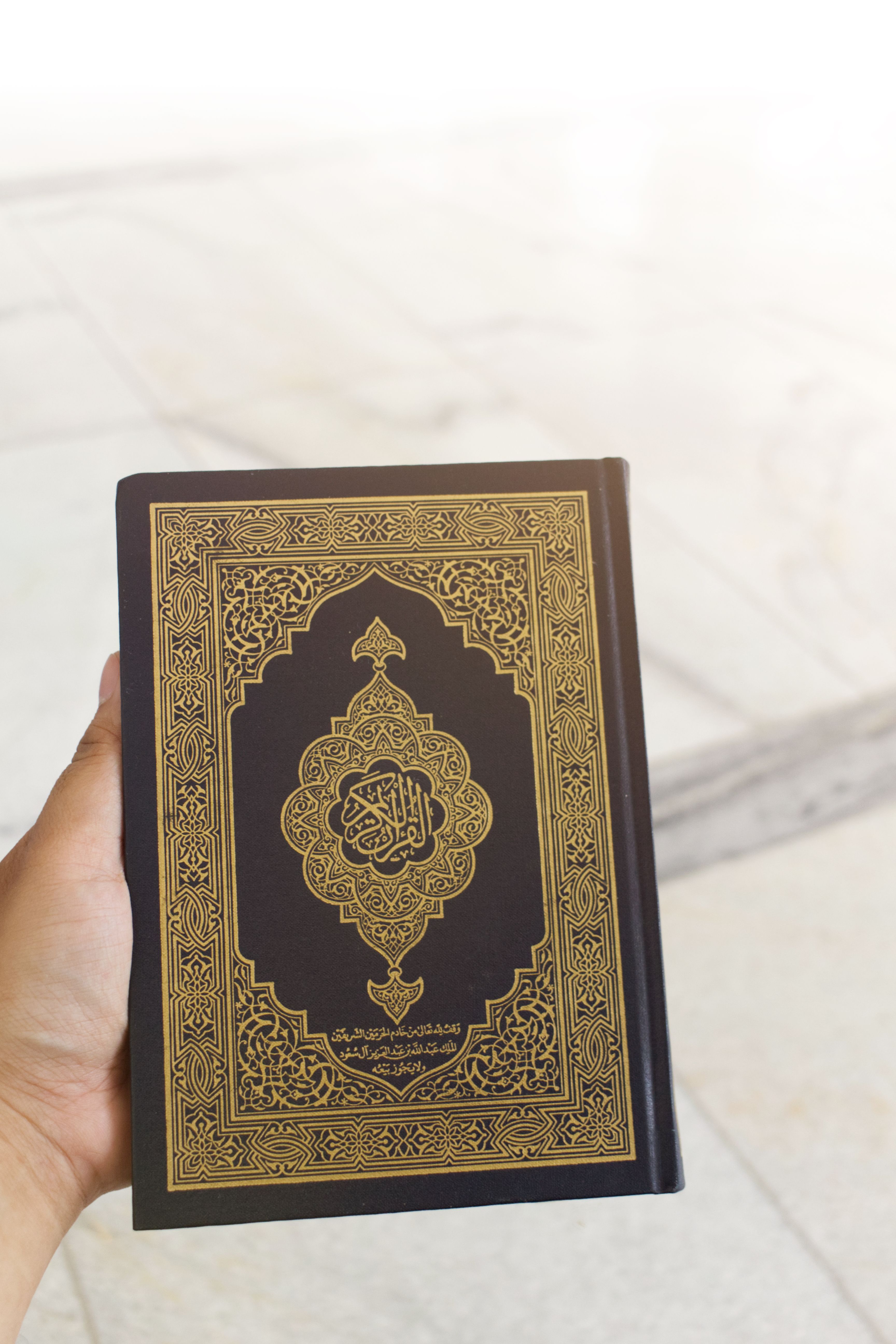 Hand Holding the Holy Quran with Arabic Calligraphy · Free Stock Photo