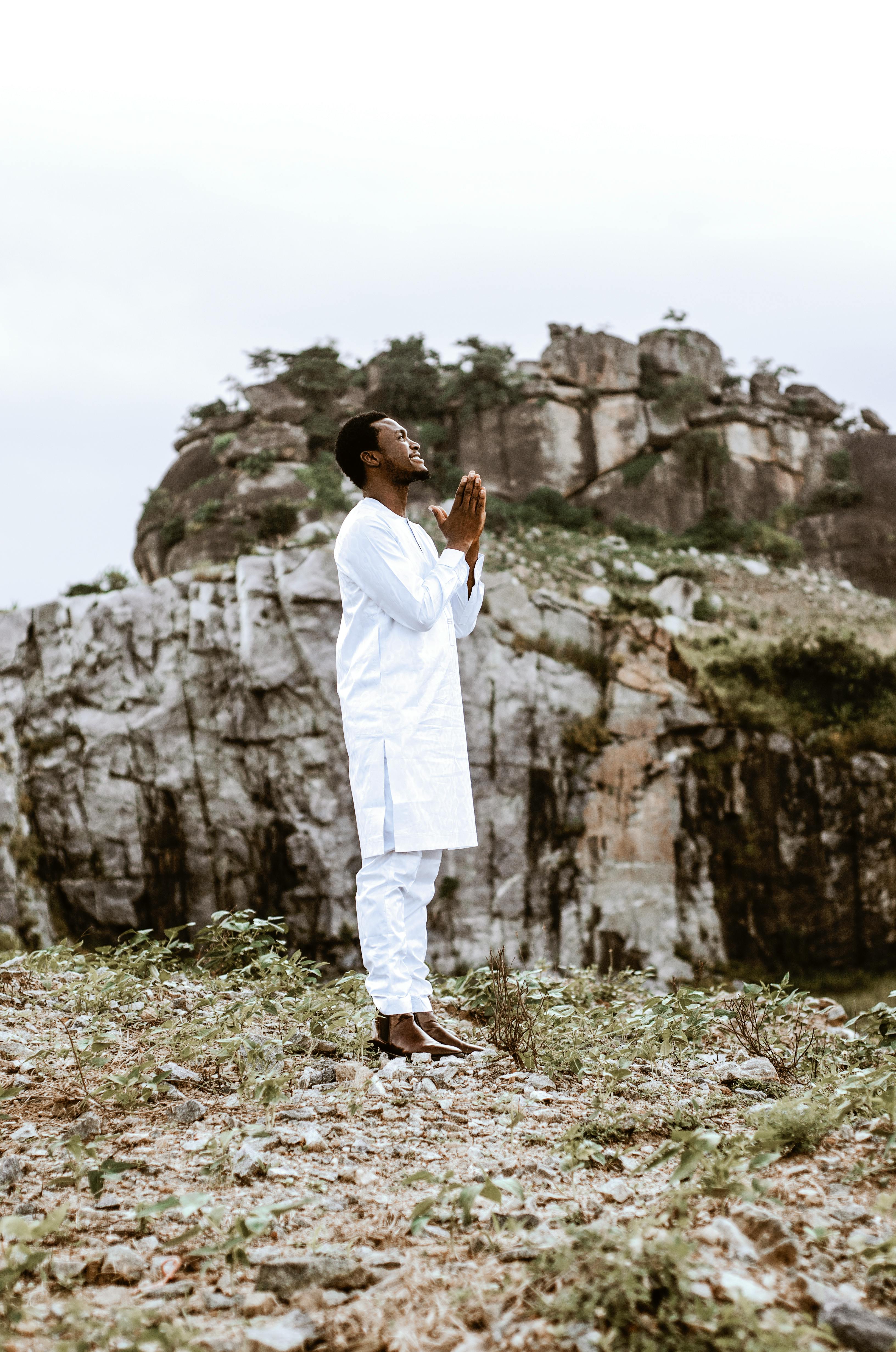 Contemplative Man Praying in Natural Rocky Terrain · Free Stock Photo