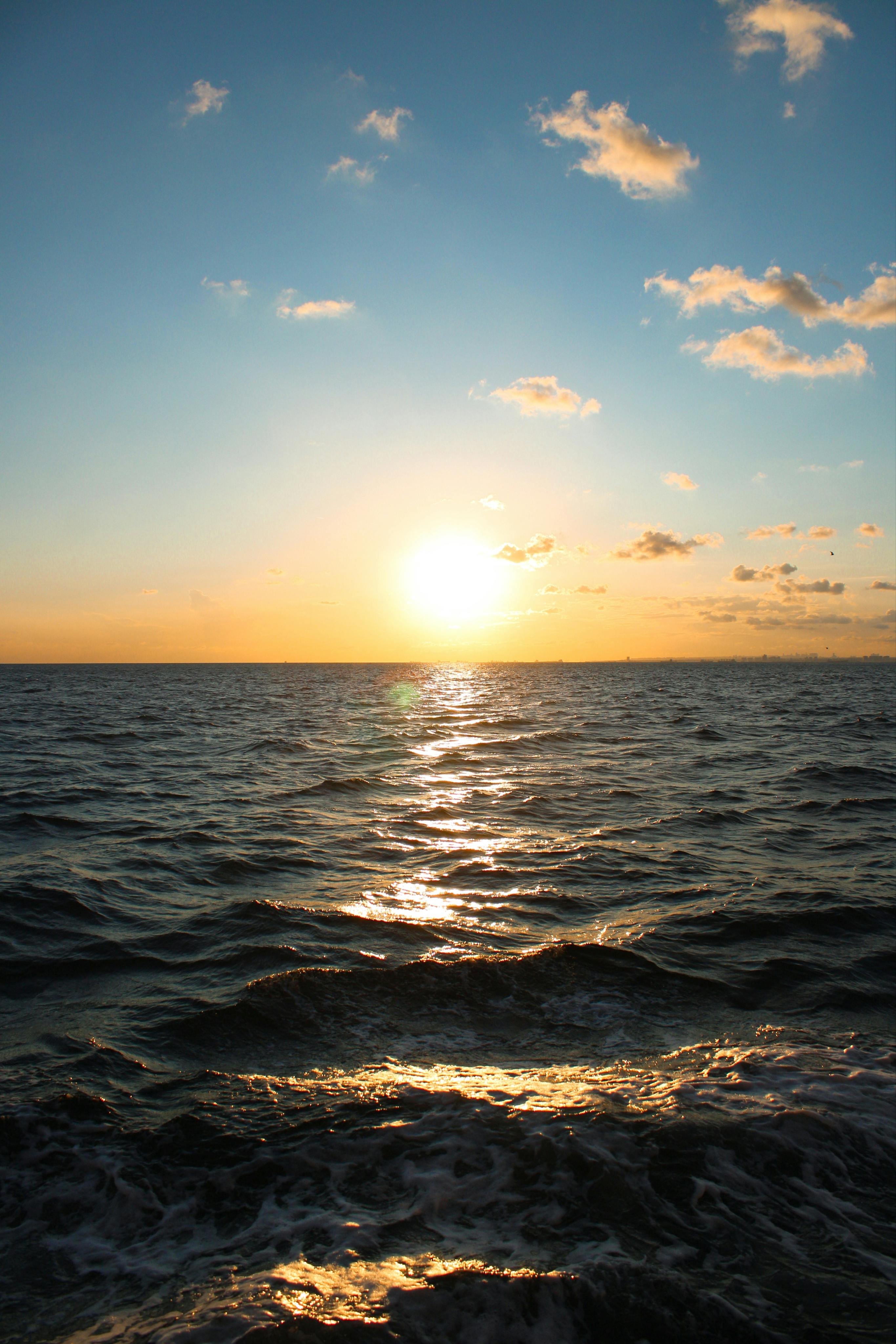 Man Taking a Picture of the Ocean on Body of Water during Golden Hour ...
