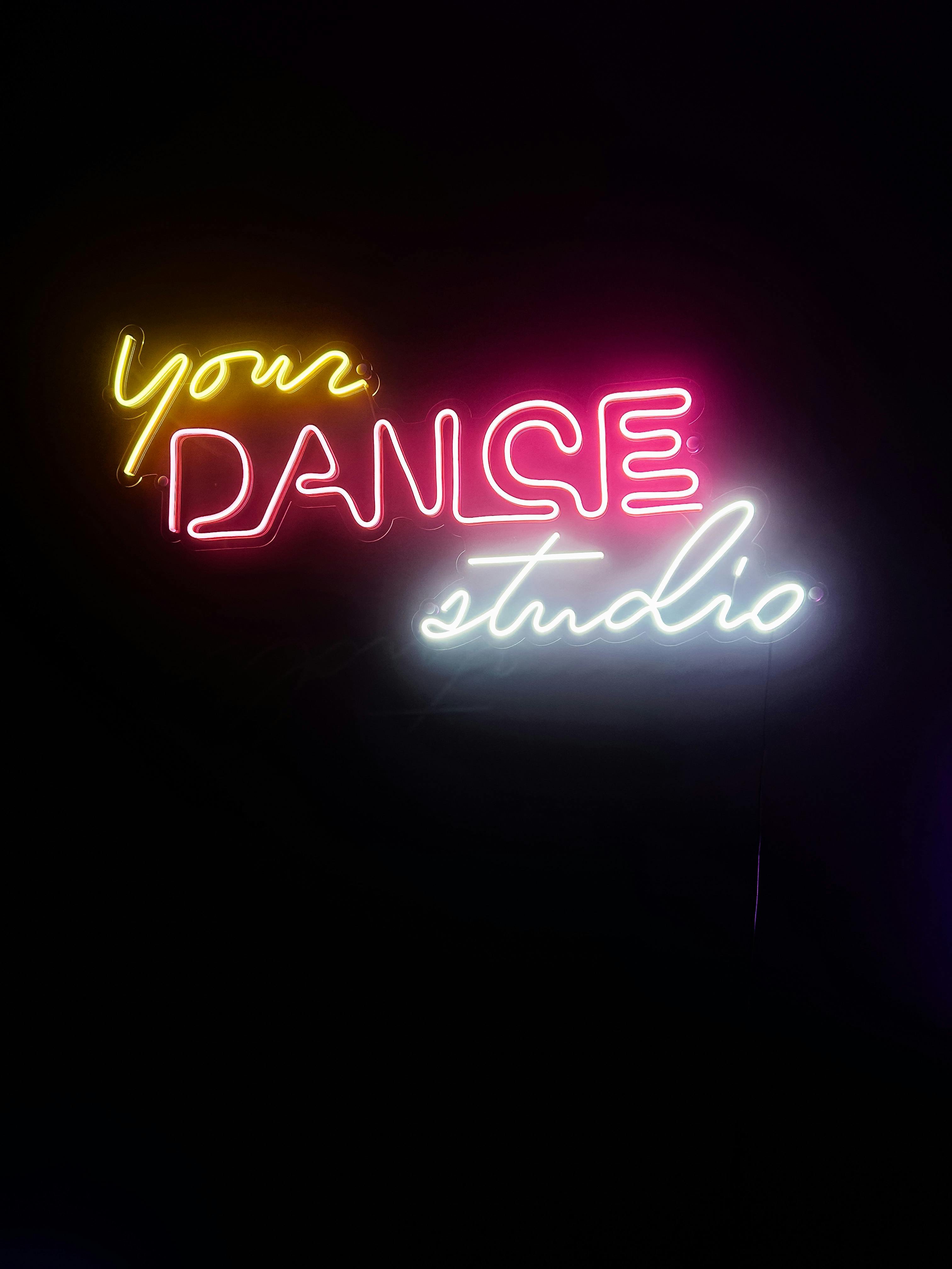 Vibrant Neon Dance Studio Sign on Dark Background · Free Stock Photo