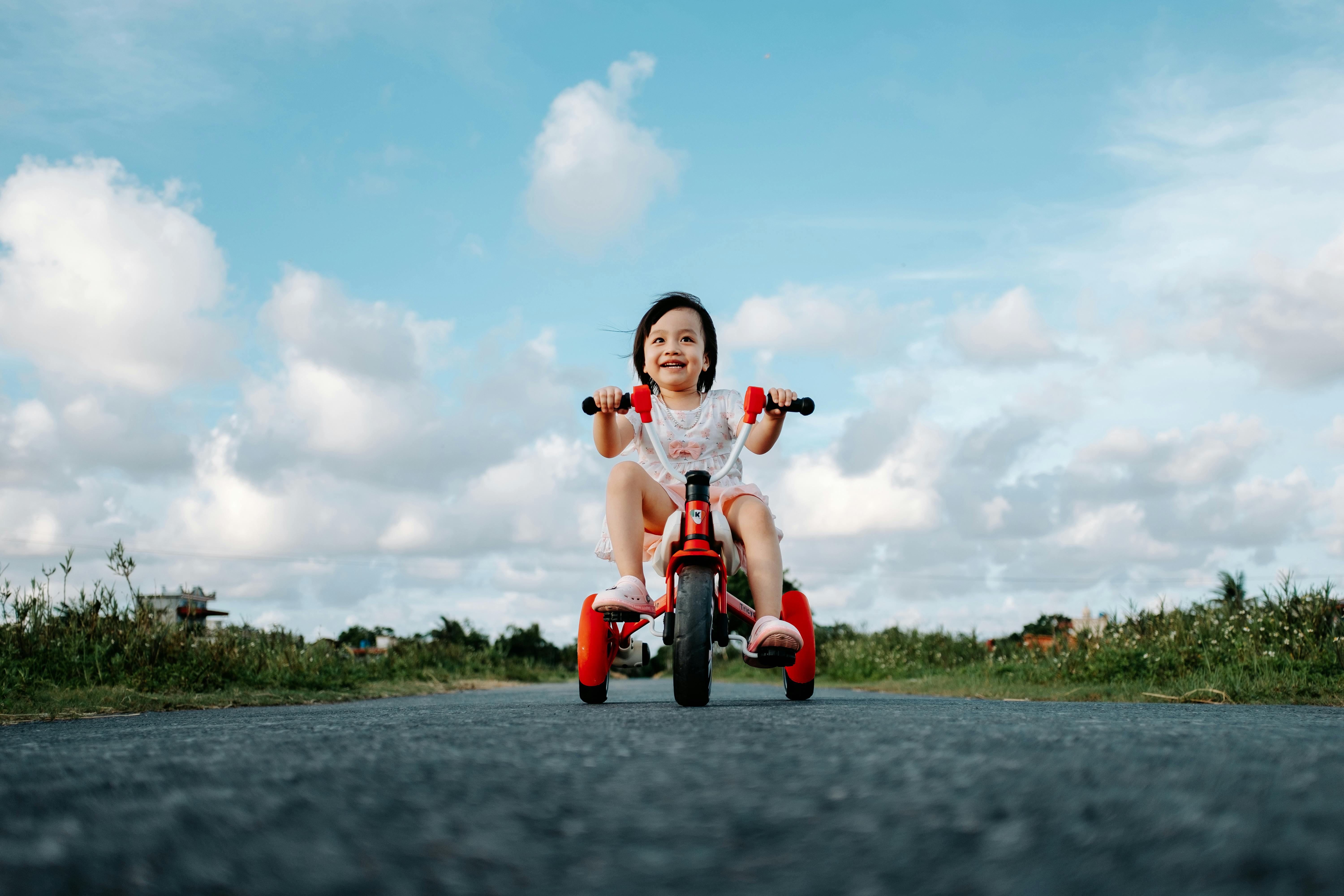 Joyful Child Riding Tricycle on Sunny Day · Free Stock Photo