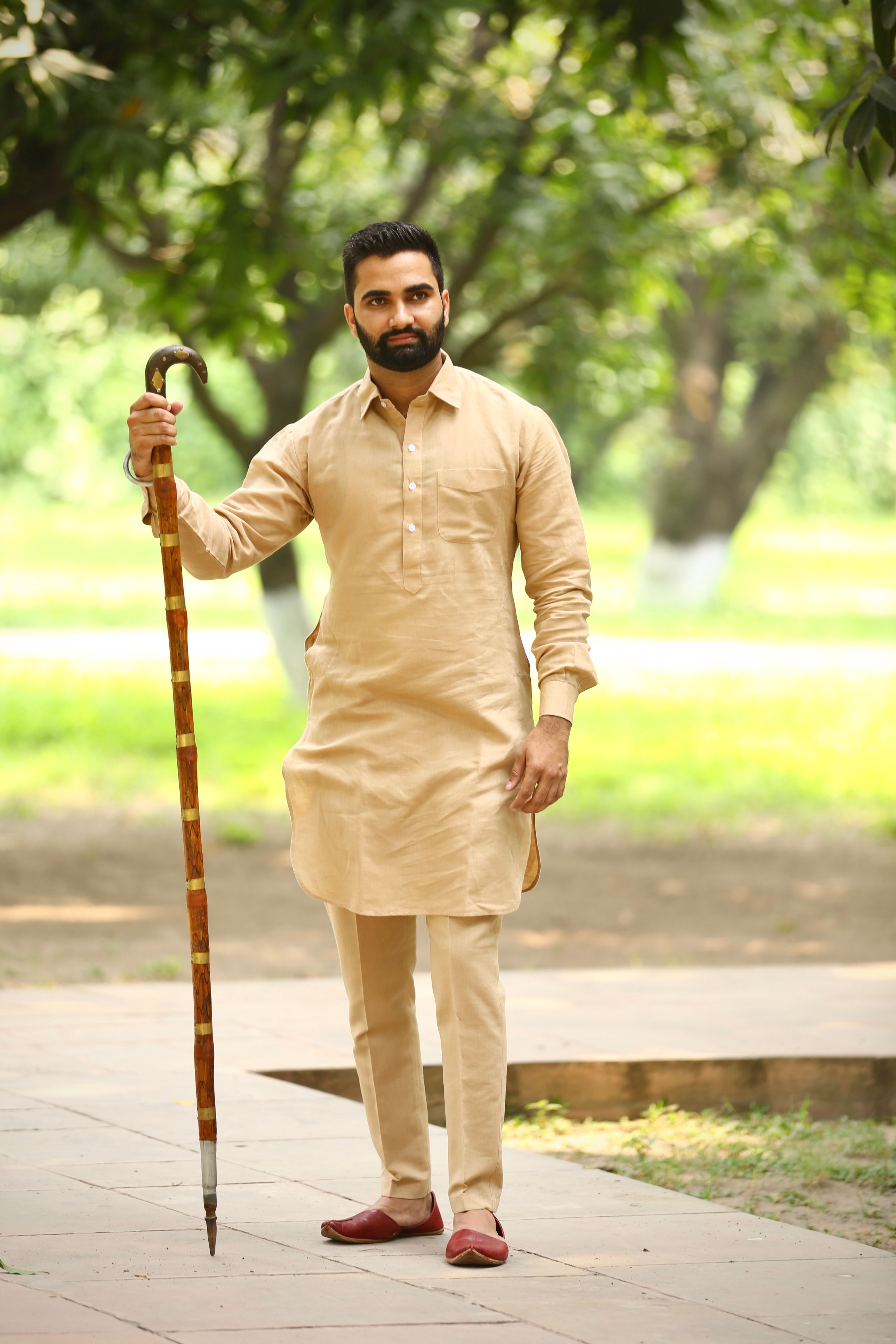 Man in Traditional Outfit with Cane in Park Setting · Free Stock Photo