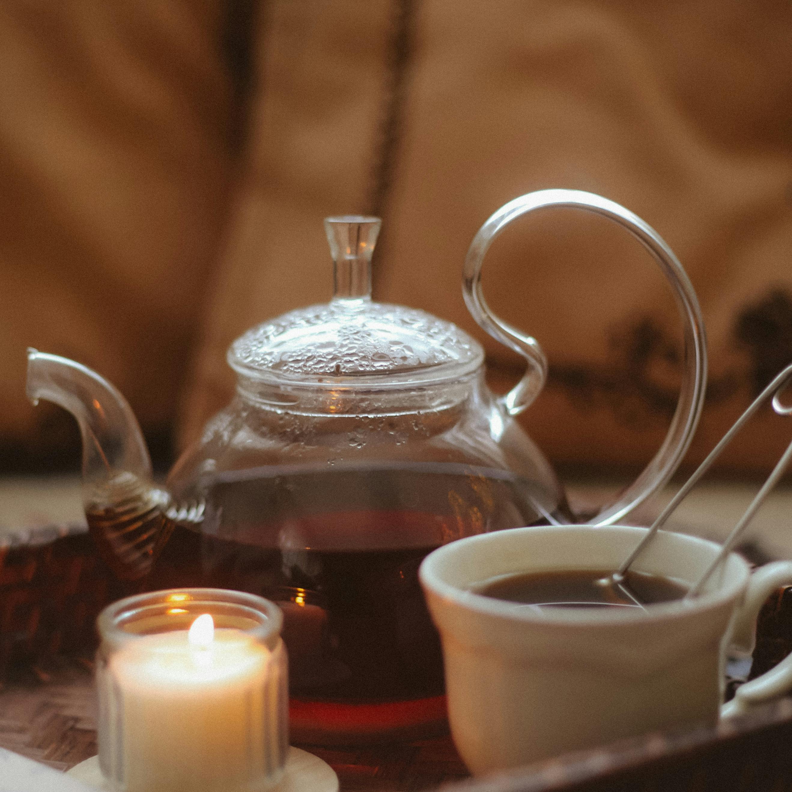 Cozy Tea Time with Glass Teapot and Candle · Free Stock Photo