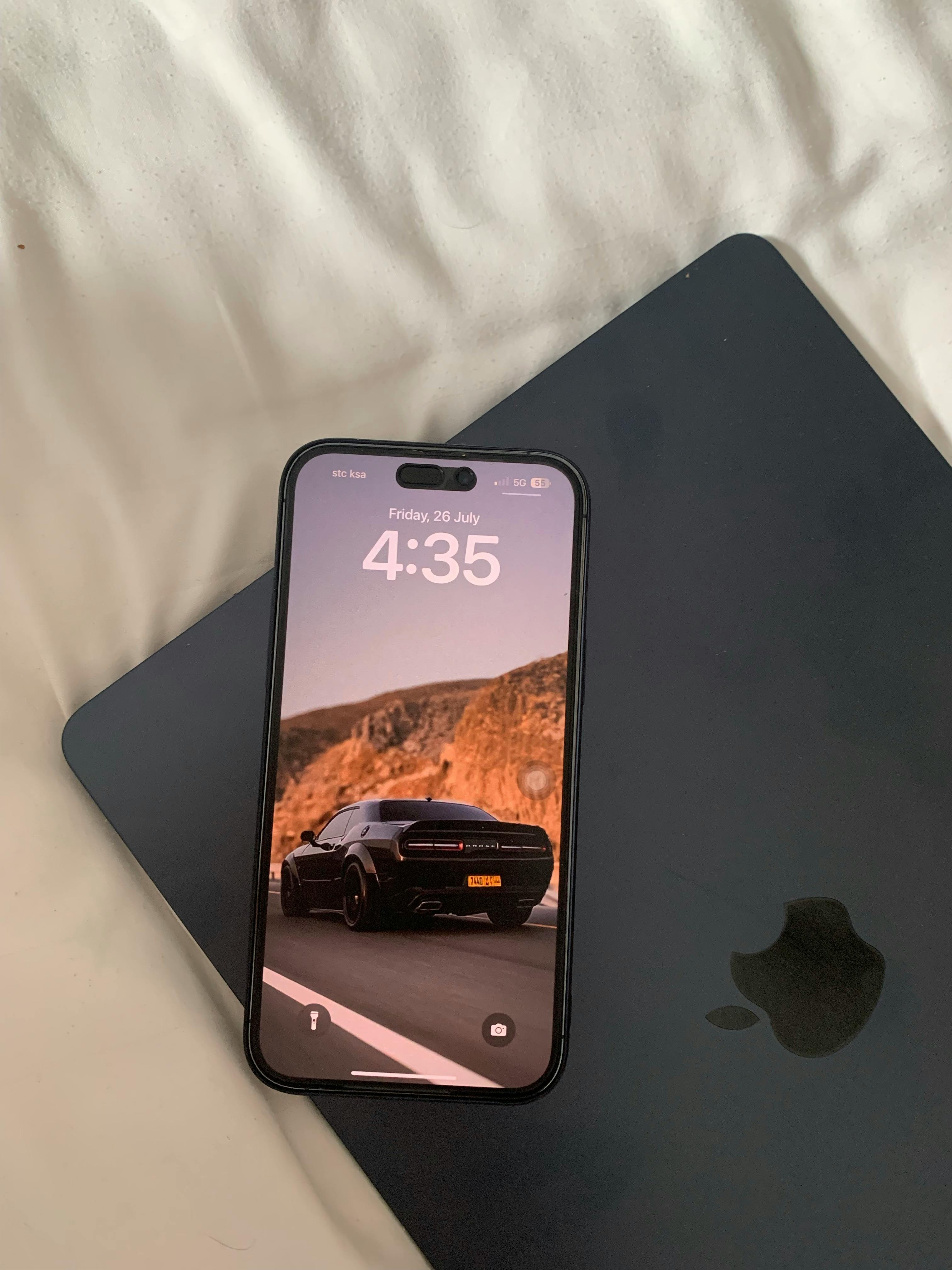 Free Smartphone displaying car wallpaper rests on a closed laptop on a ...