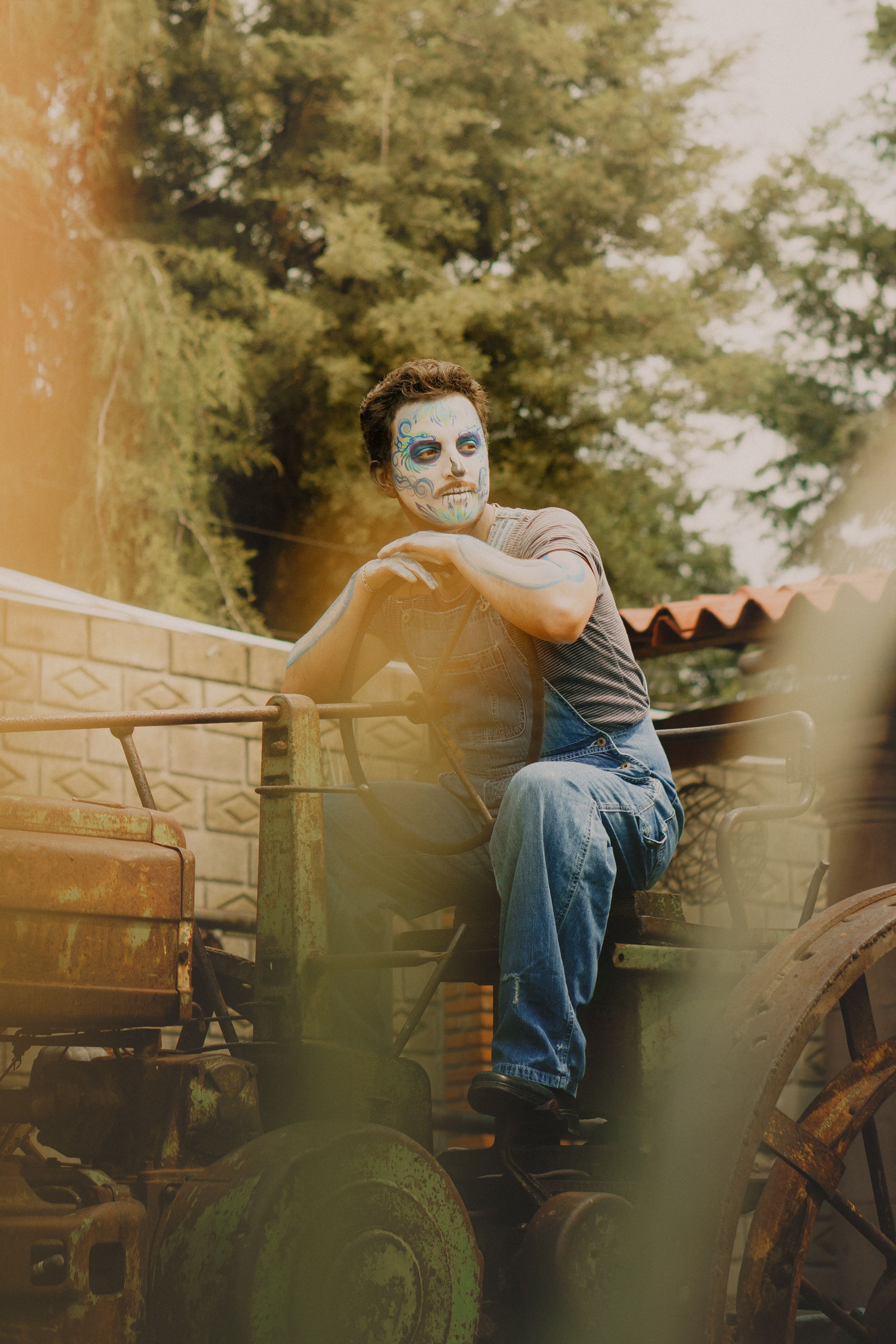Man with Face Paint Sitting on Rustic Machinery Outdoors · Free Stock Photo