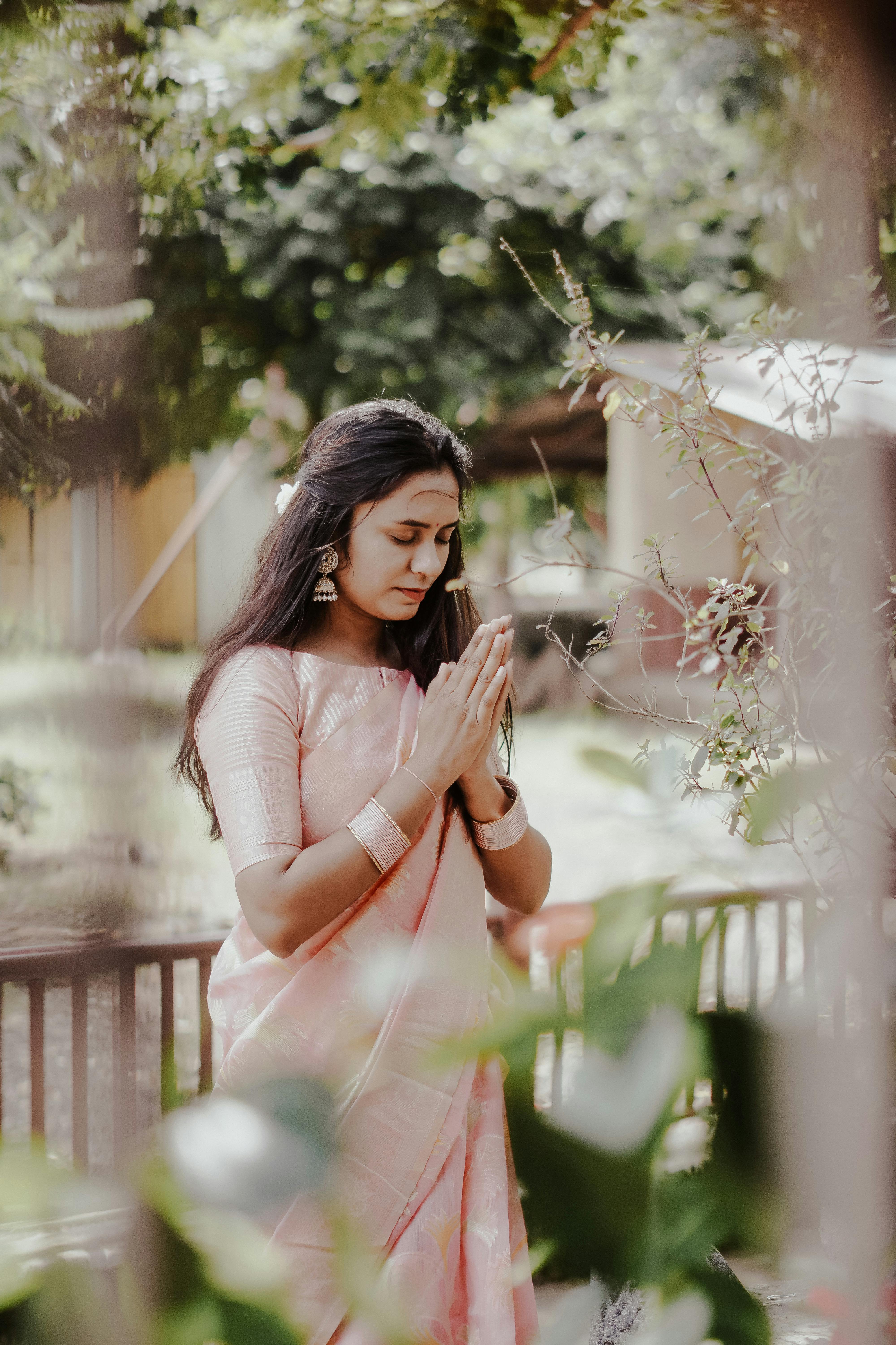 Young Woman in Traditional Indian Saree Praying Outdoors · Free Stock Photo