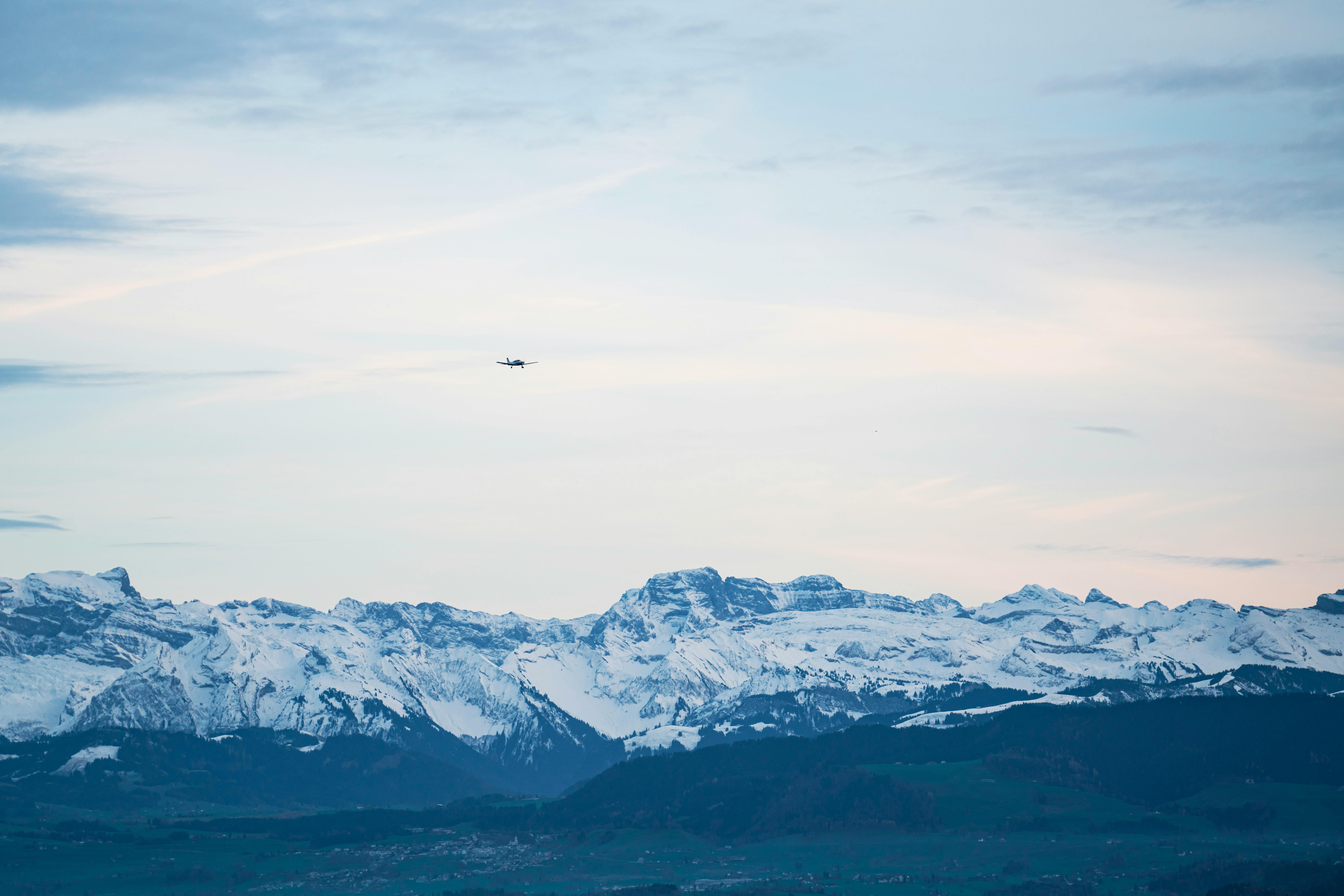 Airplane Flying Over Snow-Capped Mountain Range · Free Stock Photo