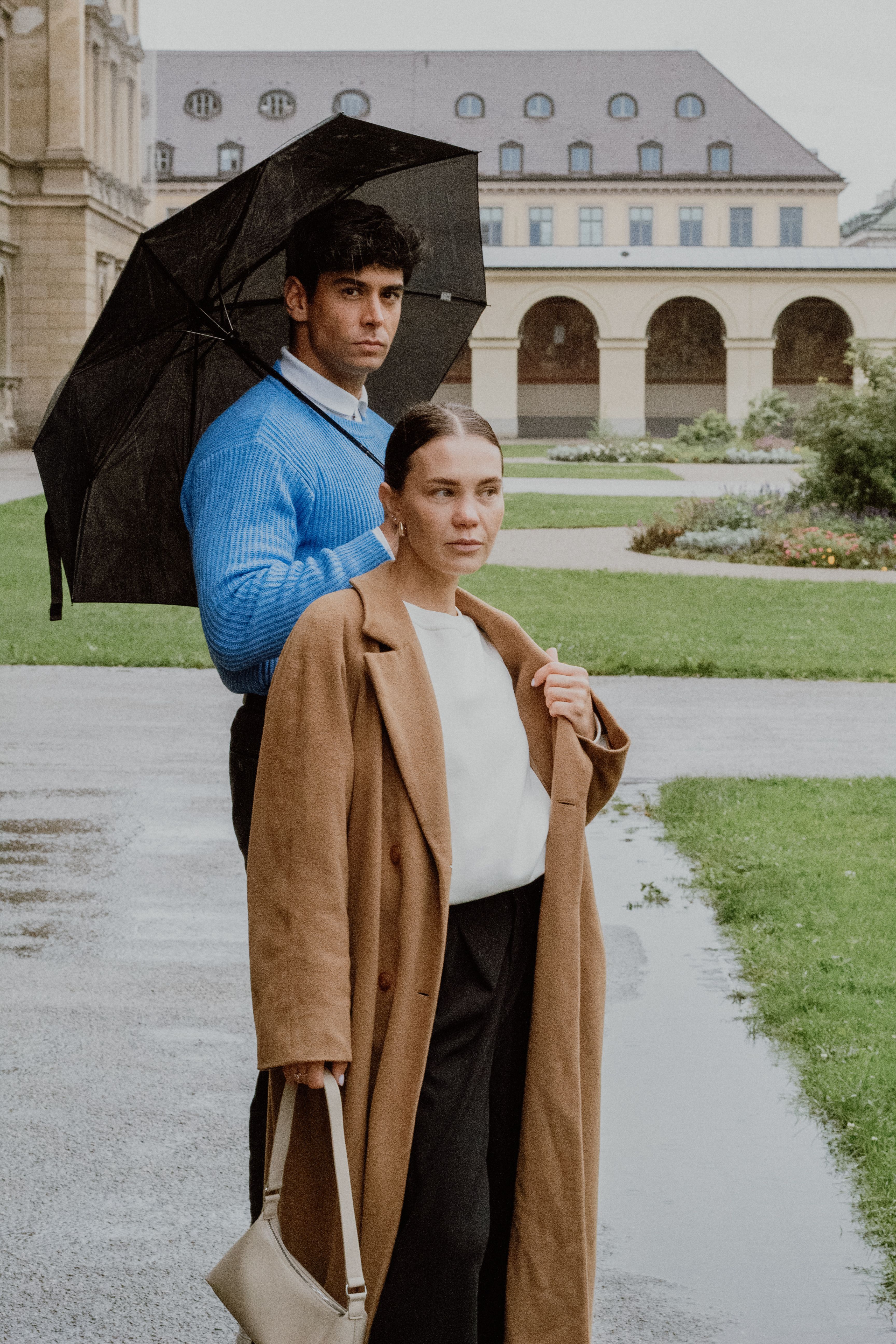 Couple Posing Under Umbrella Outside Historic Building · Free Stock Photo