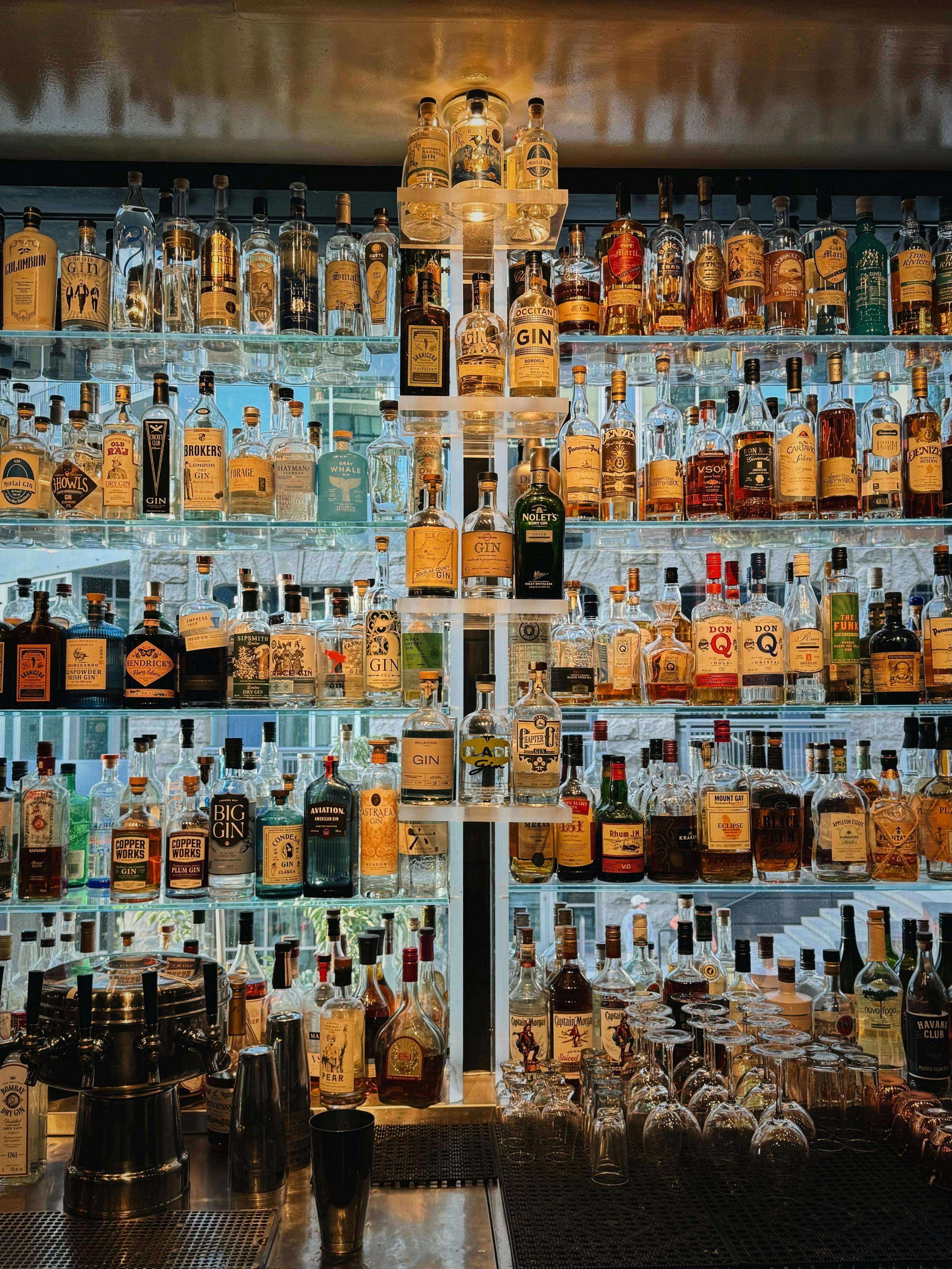 Vibrant Array of Liquor Bottles on Bar Shelves · Free Stock Photo
