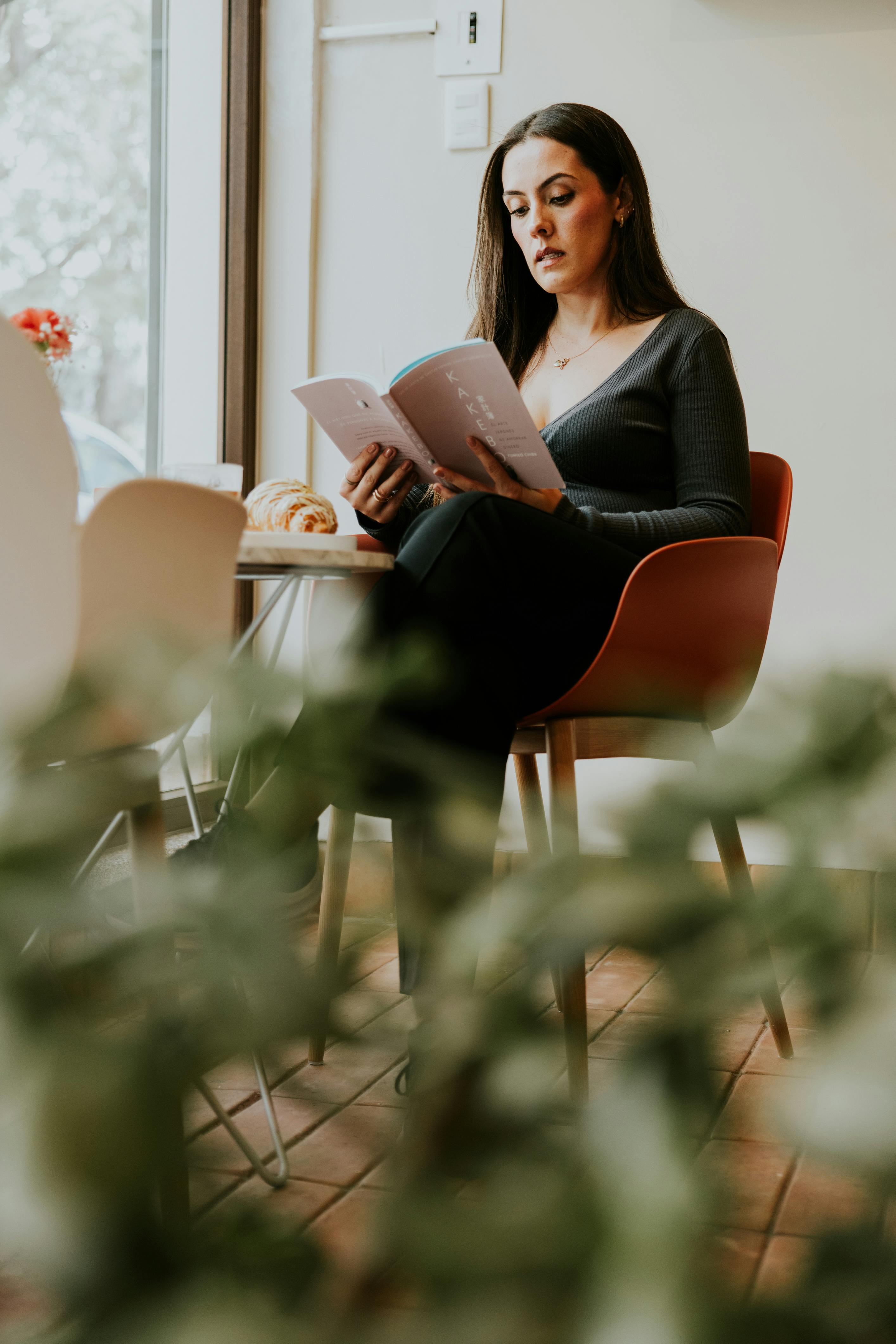 Woman Reading with Coffee in Cozy Cafe Setting · Free Stock Photo