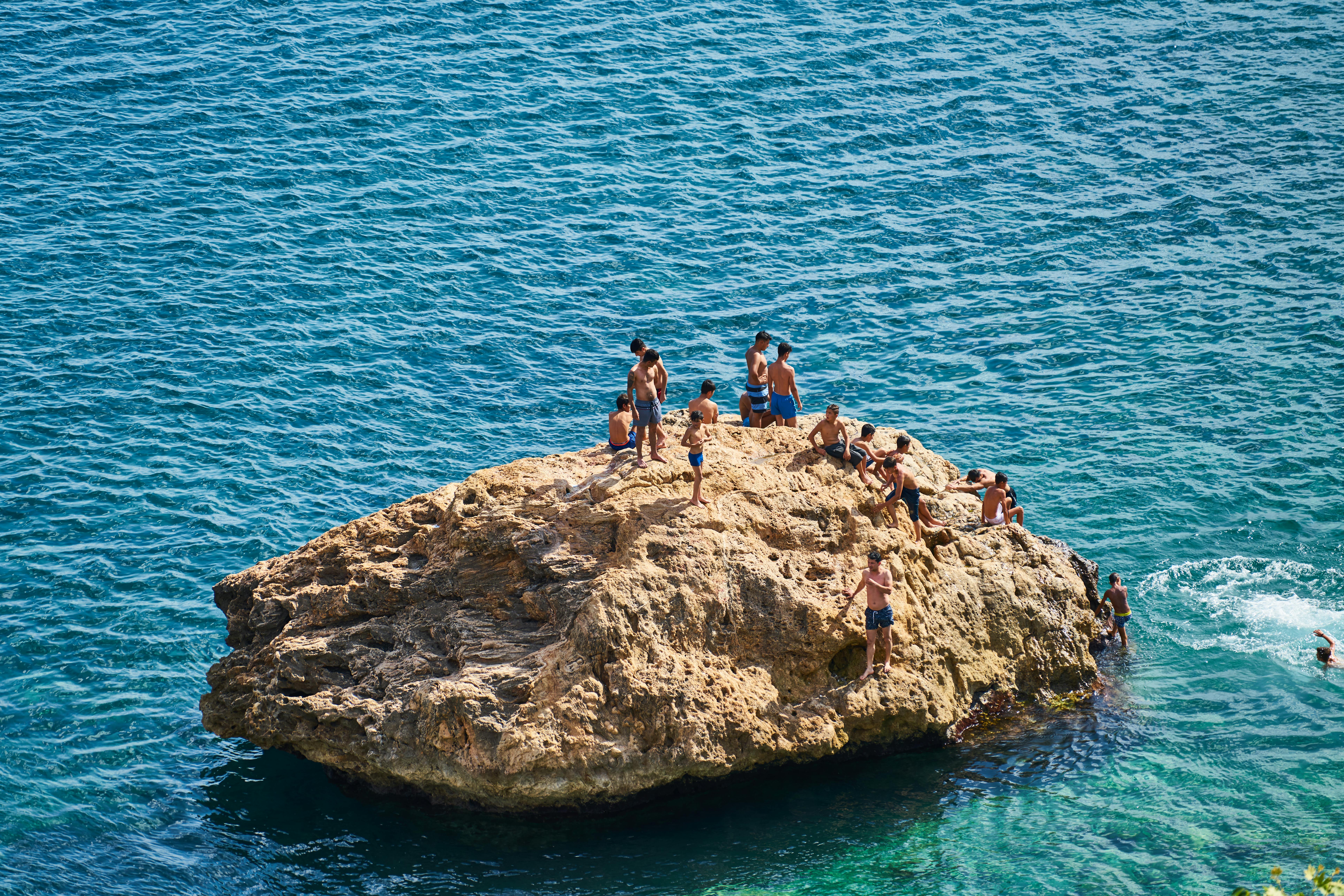 People Gathering On A Rock Formation In The Sea · Free Stock Photo