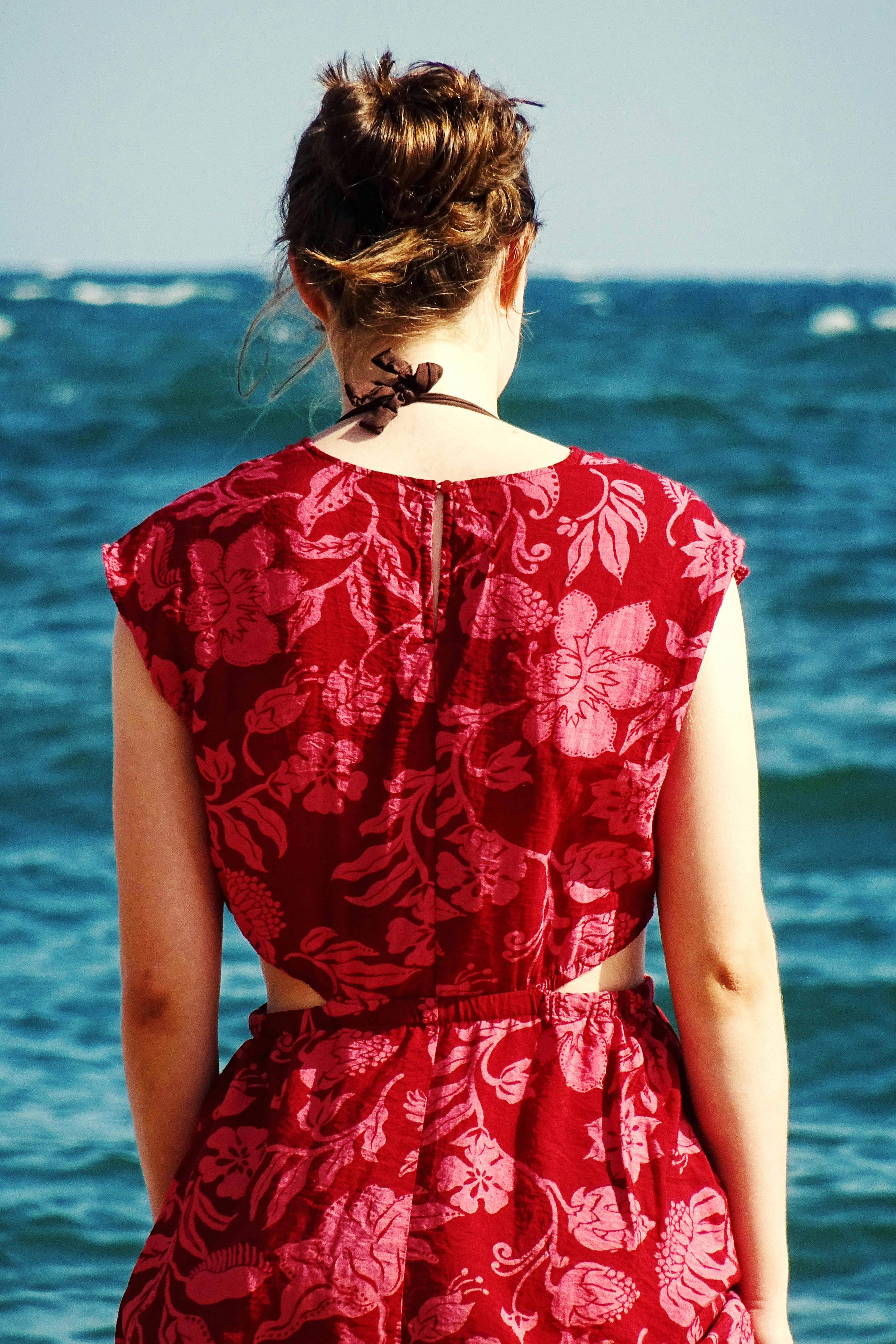 Woman in Red Floral Dress Facing Ocean · Free Stock Photo