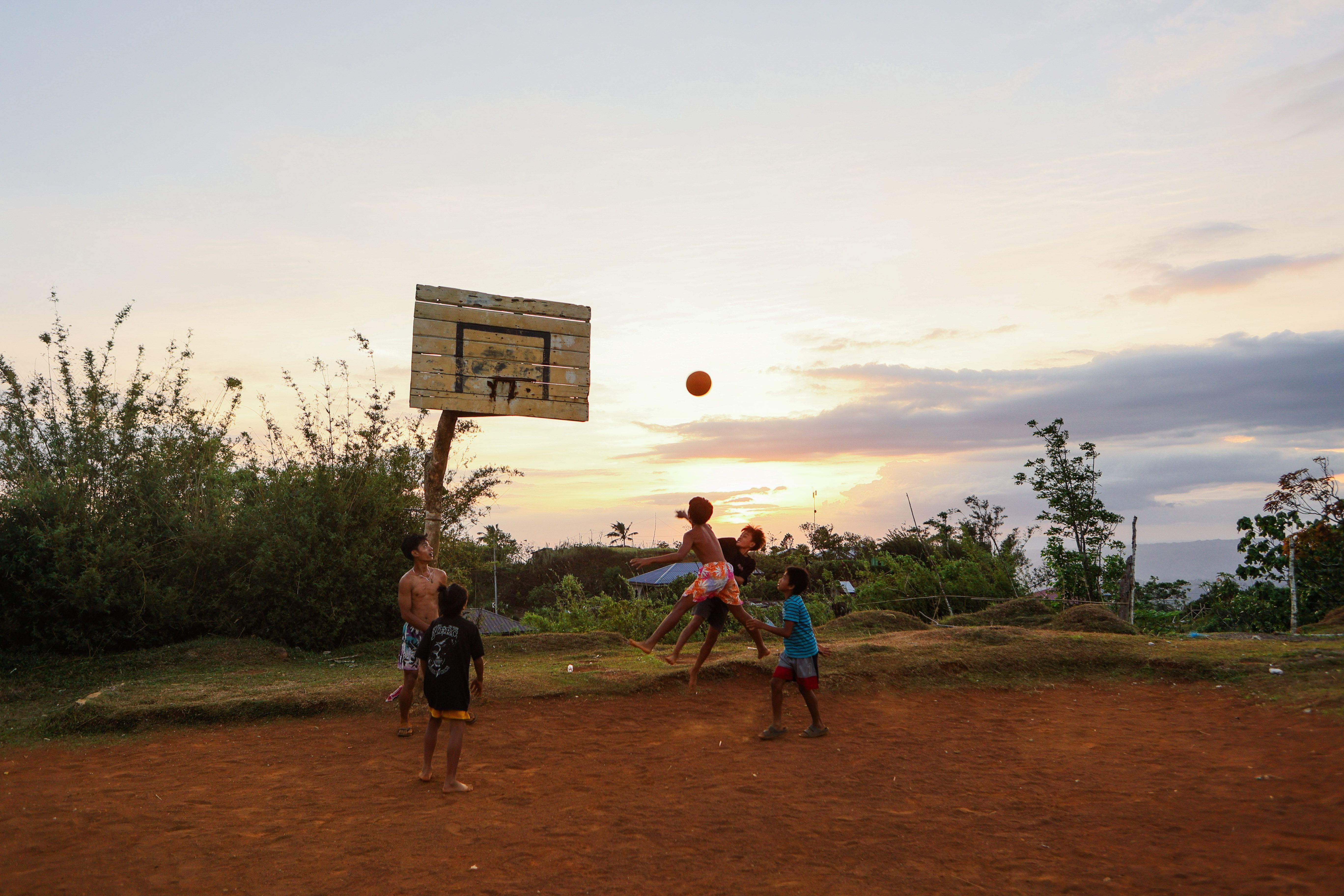 Niños Jugando Al Baloncesto Al Atardecer En La Cancha De Tierra · Foto ...