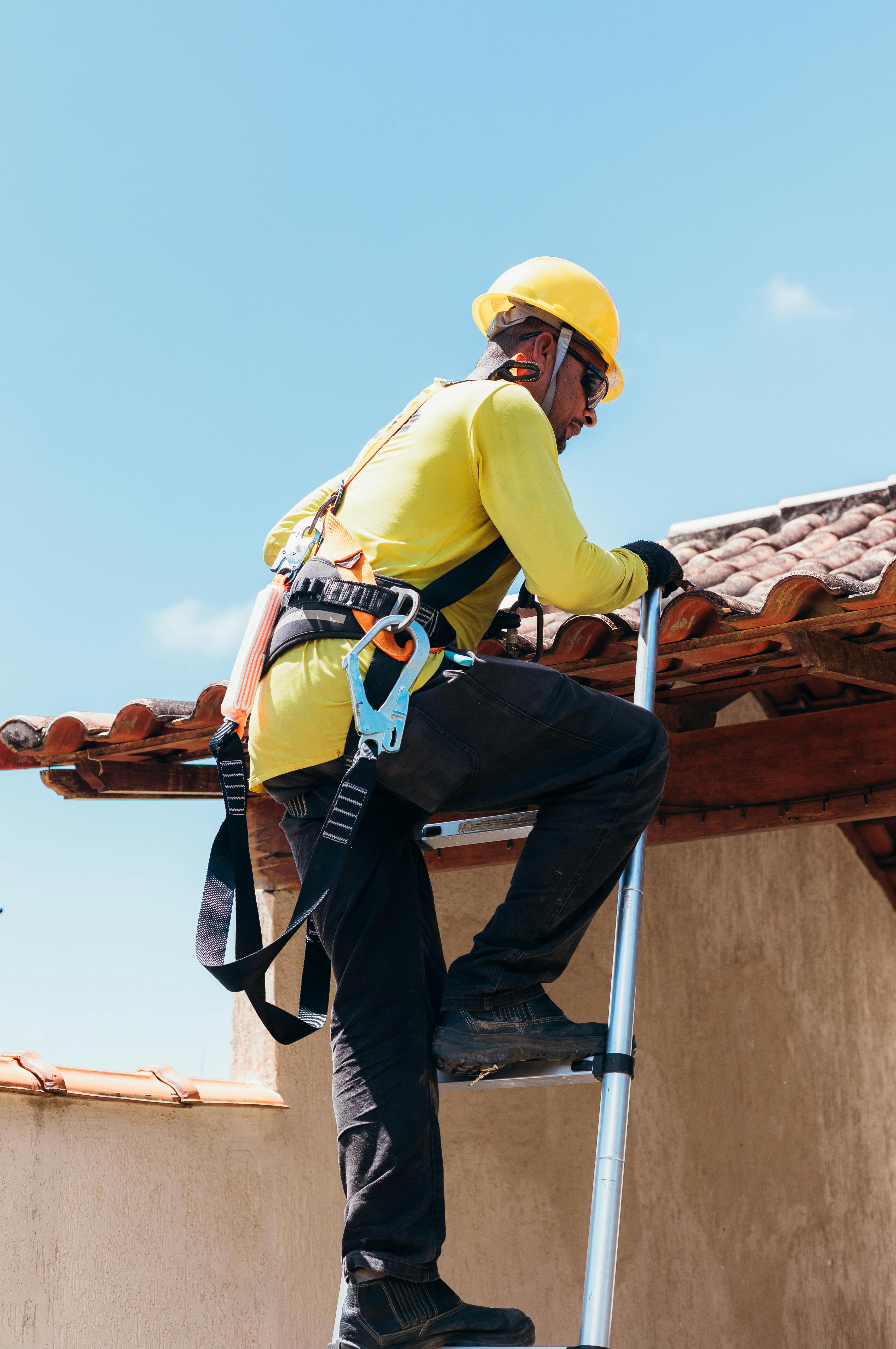 Construction Worker Climbing Ladder at Worksite · Free Stock Photo