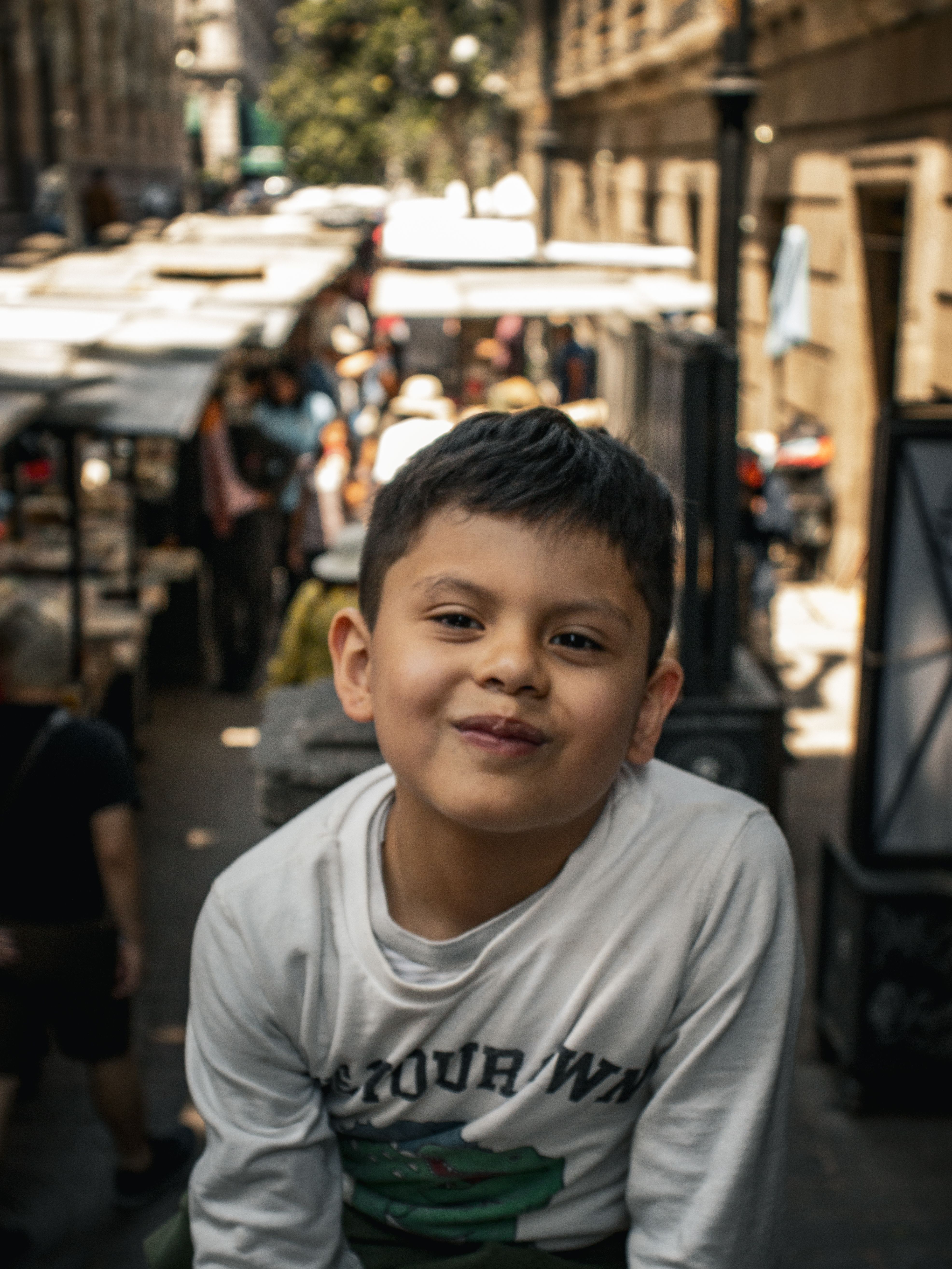 Smiling Child in a Busy Street Market · Free Stock Photo