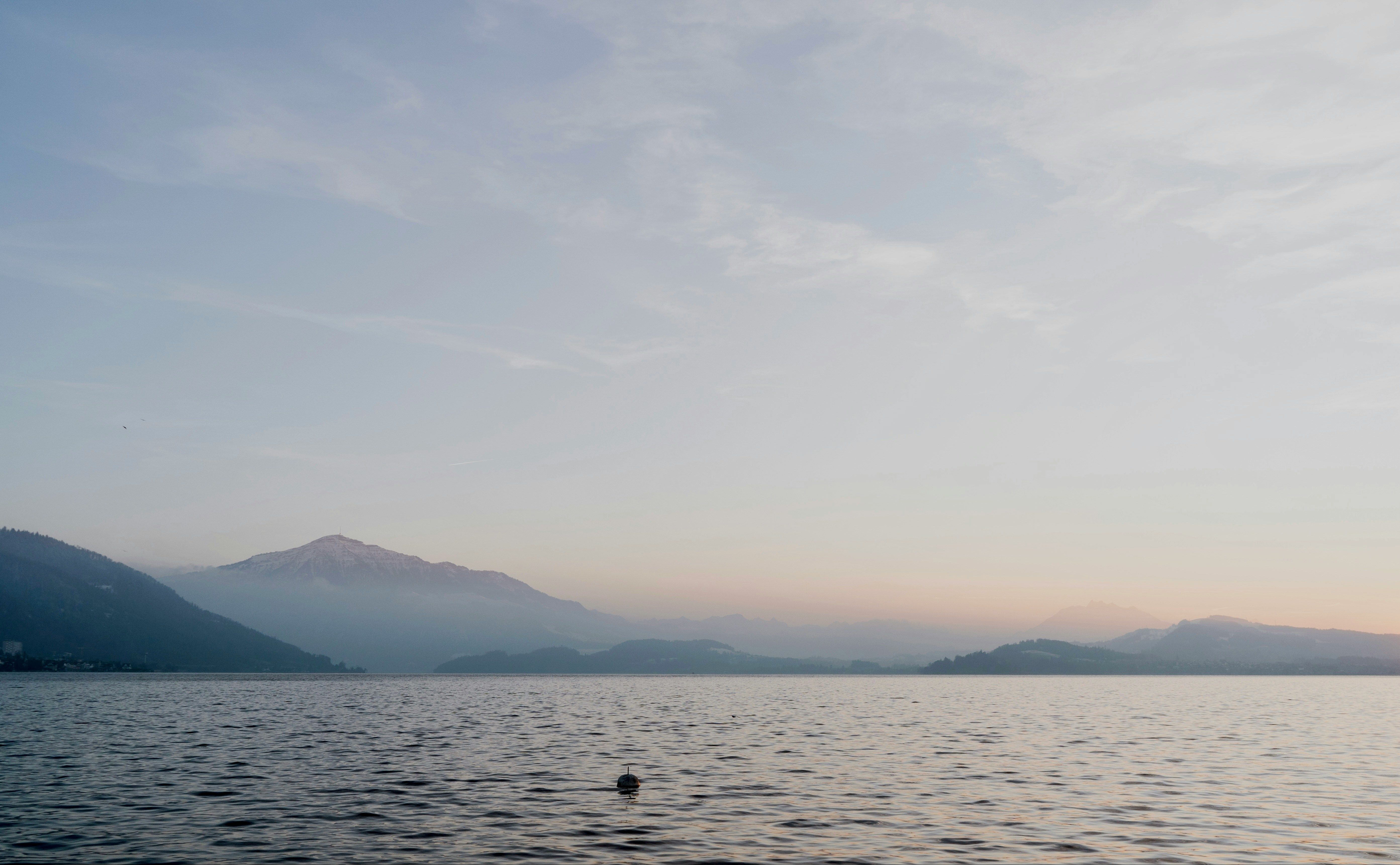 Calm Lake View with Distant Mountains at Sunrise · Free Stock Photo