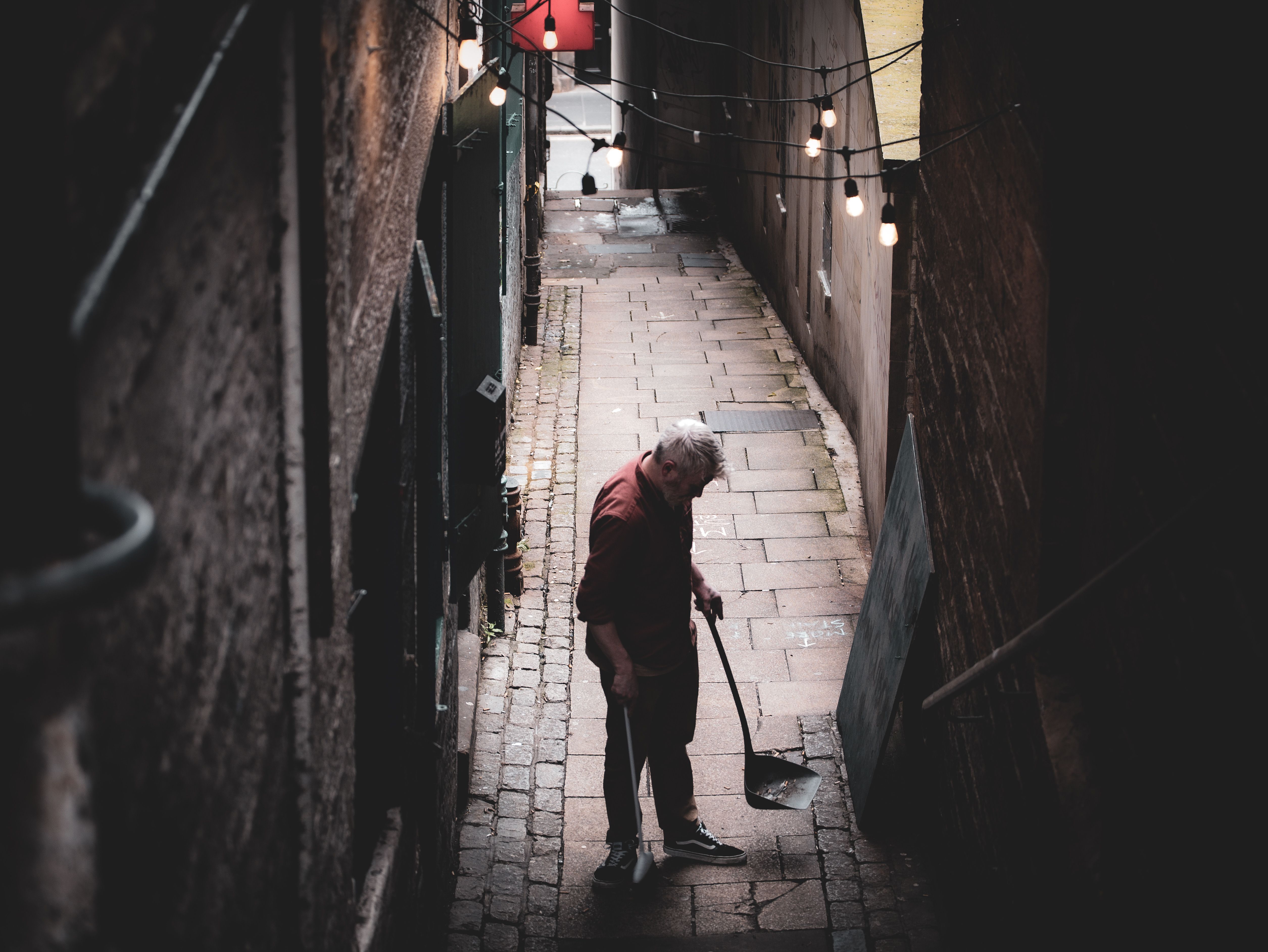 Man Cleaning Narrow Alley with String Lights · Free Stock Photo