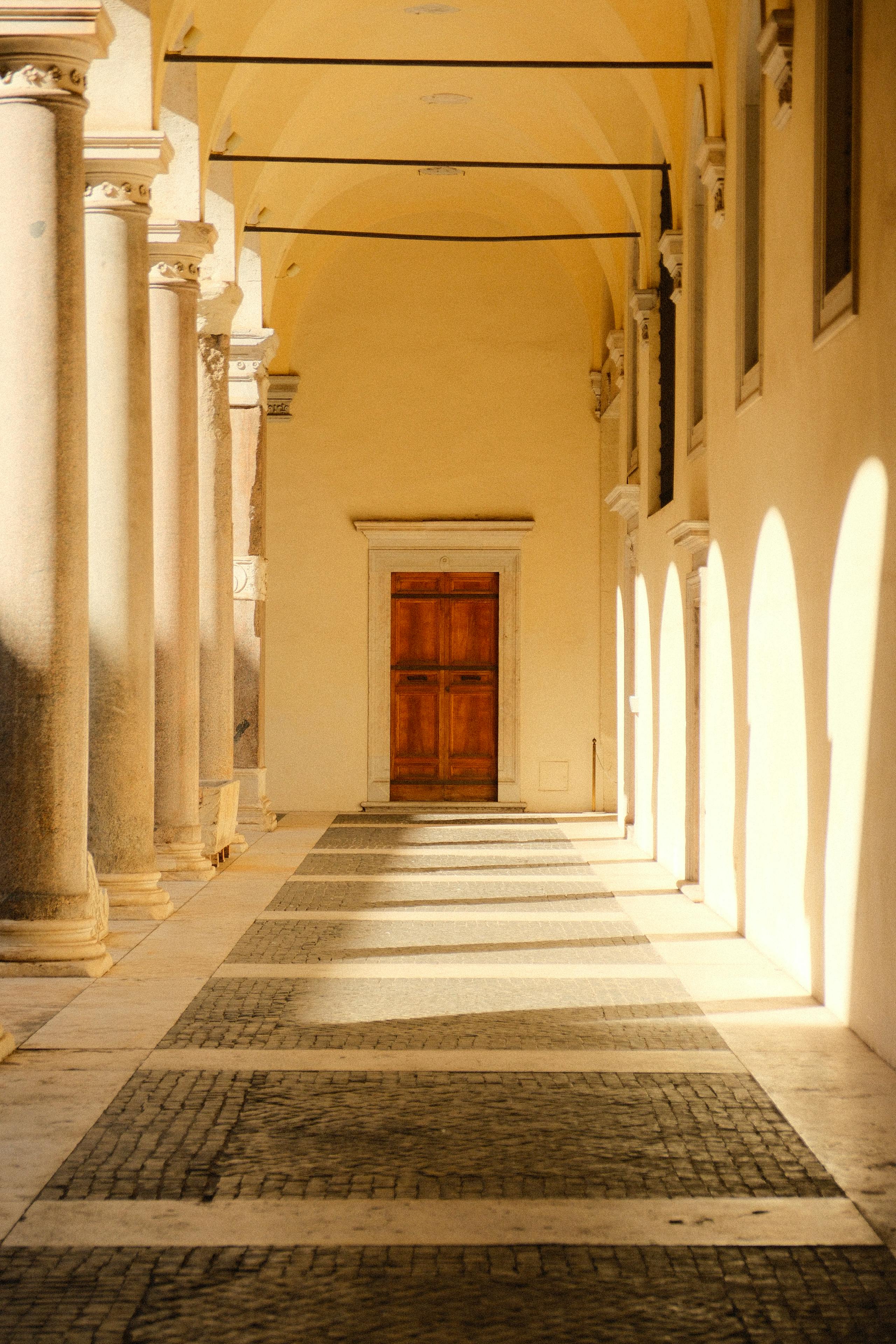 Elegant Sunlit Arcaded Corridor with Doorway · Free Stock Photo