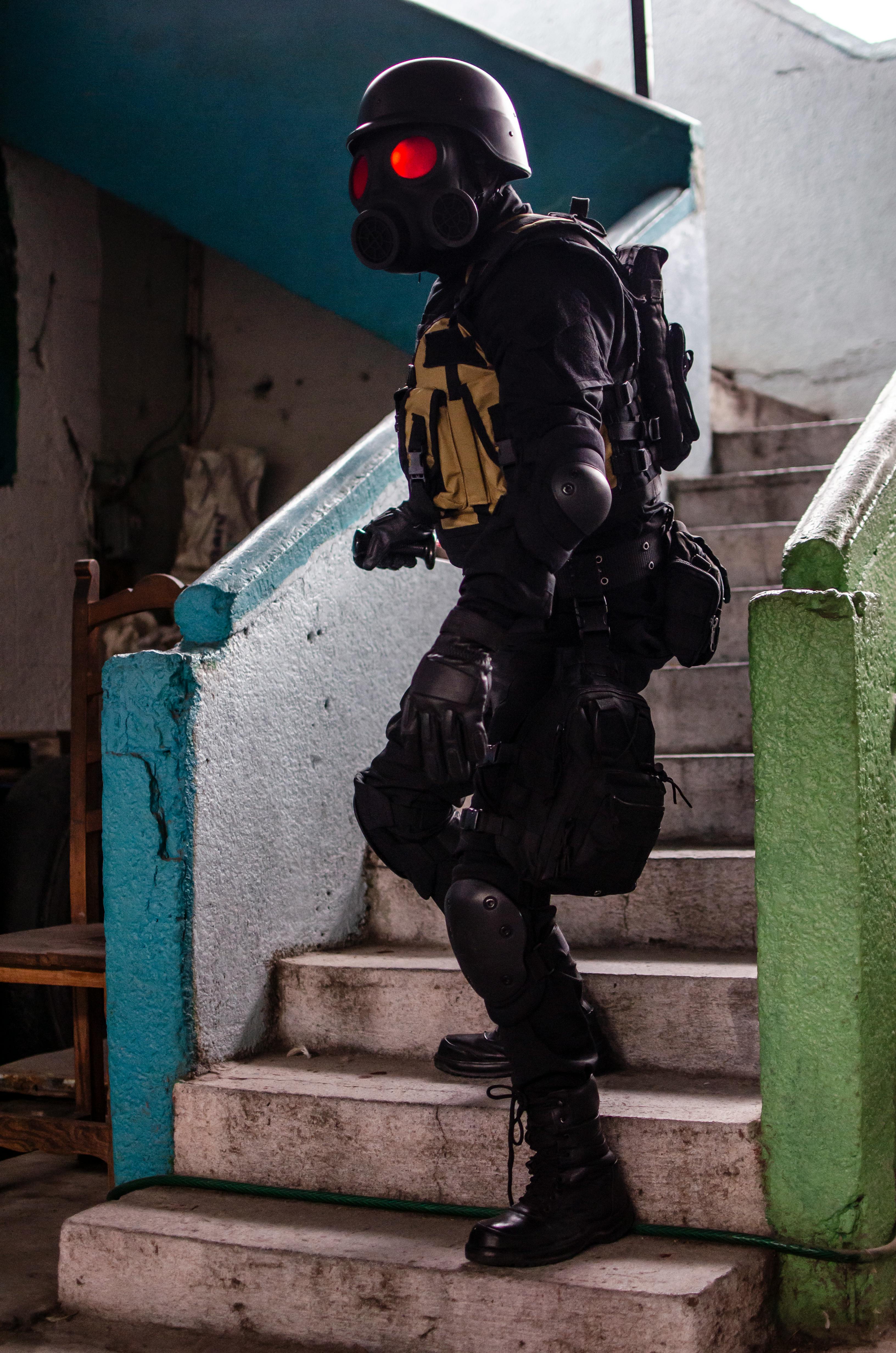 Tactical Cosplay Character with Red Eyes Ascends Stairs · Free Stock Photo