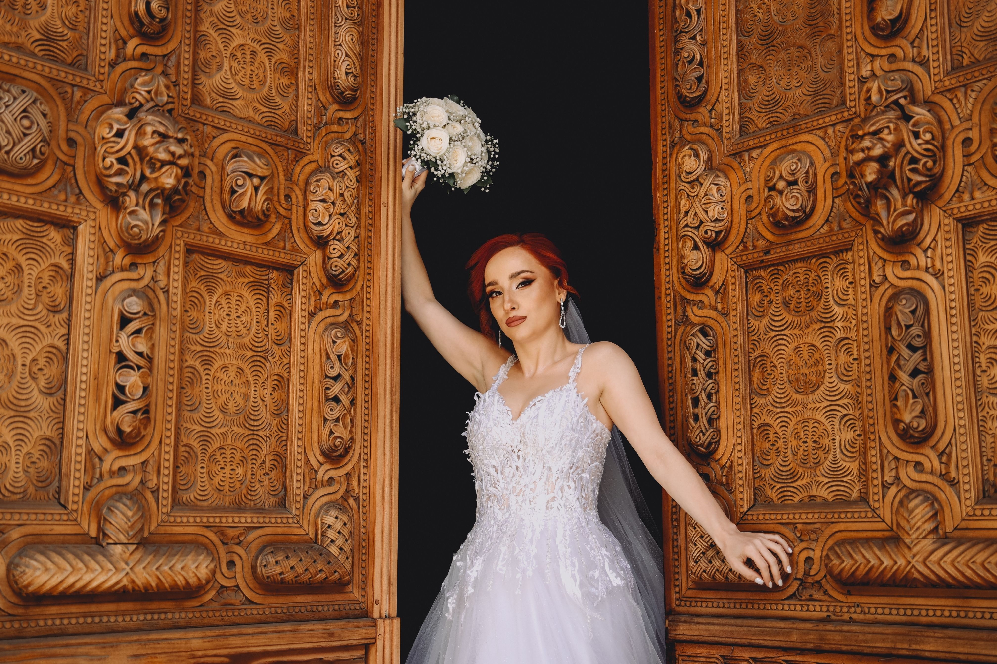 Elegant Bride Posing in Ornate Wooden Doorway · Free Stock Photo