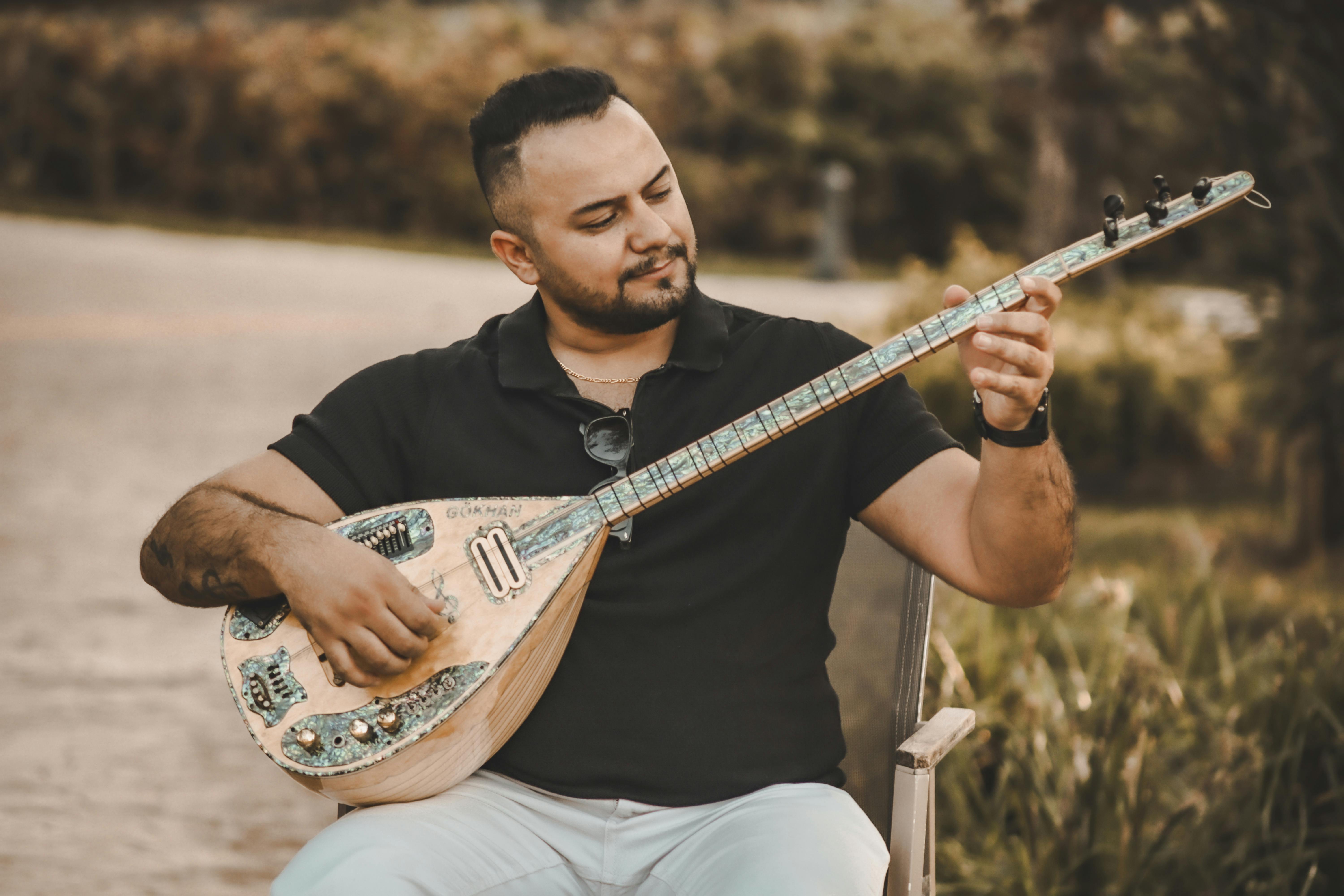 Man Playing Turkish Baglama in Outdoor Setting · Free Stock Photo