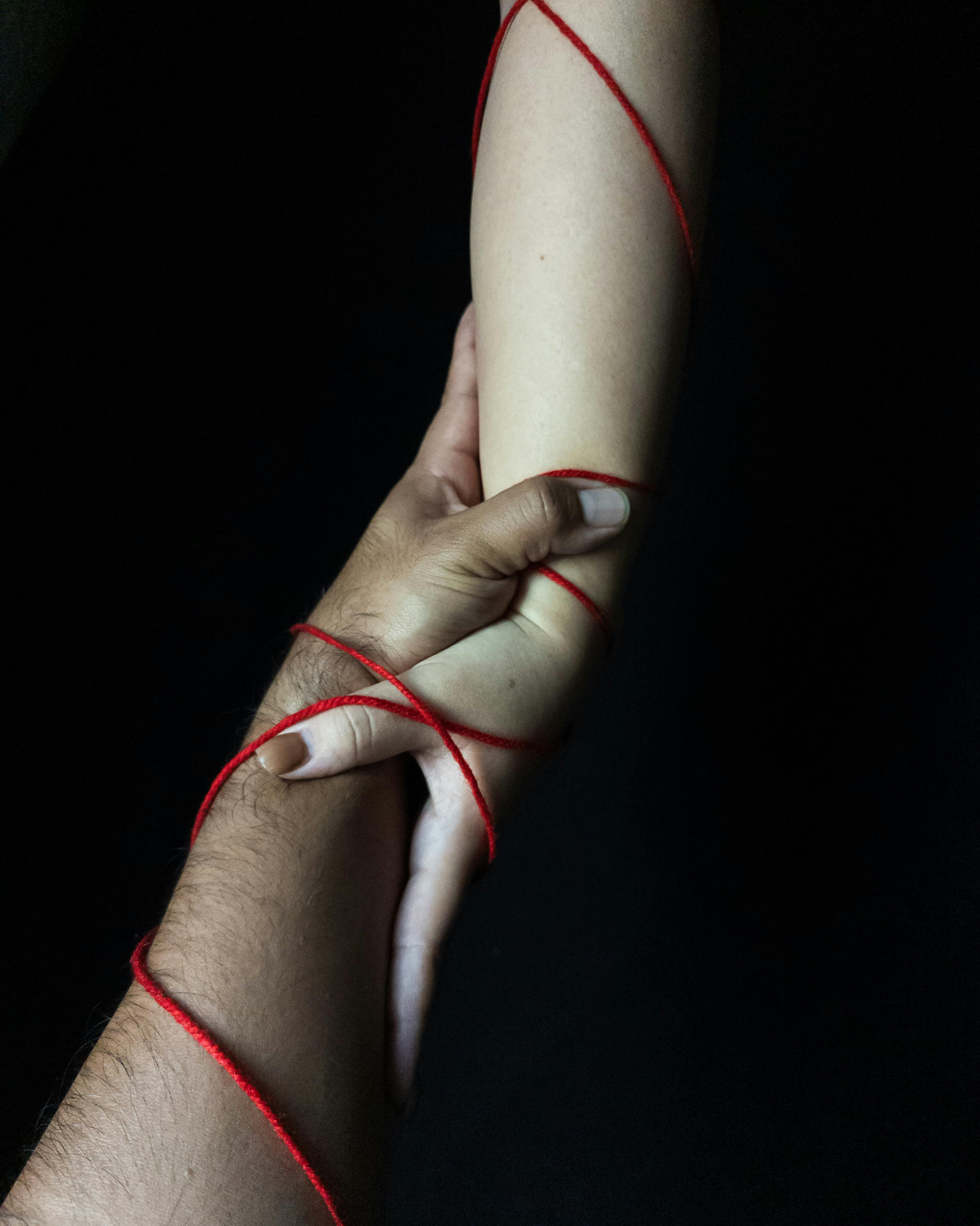 Intertwined Hands with Red String Symbolism · Free Stock Photo
