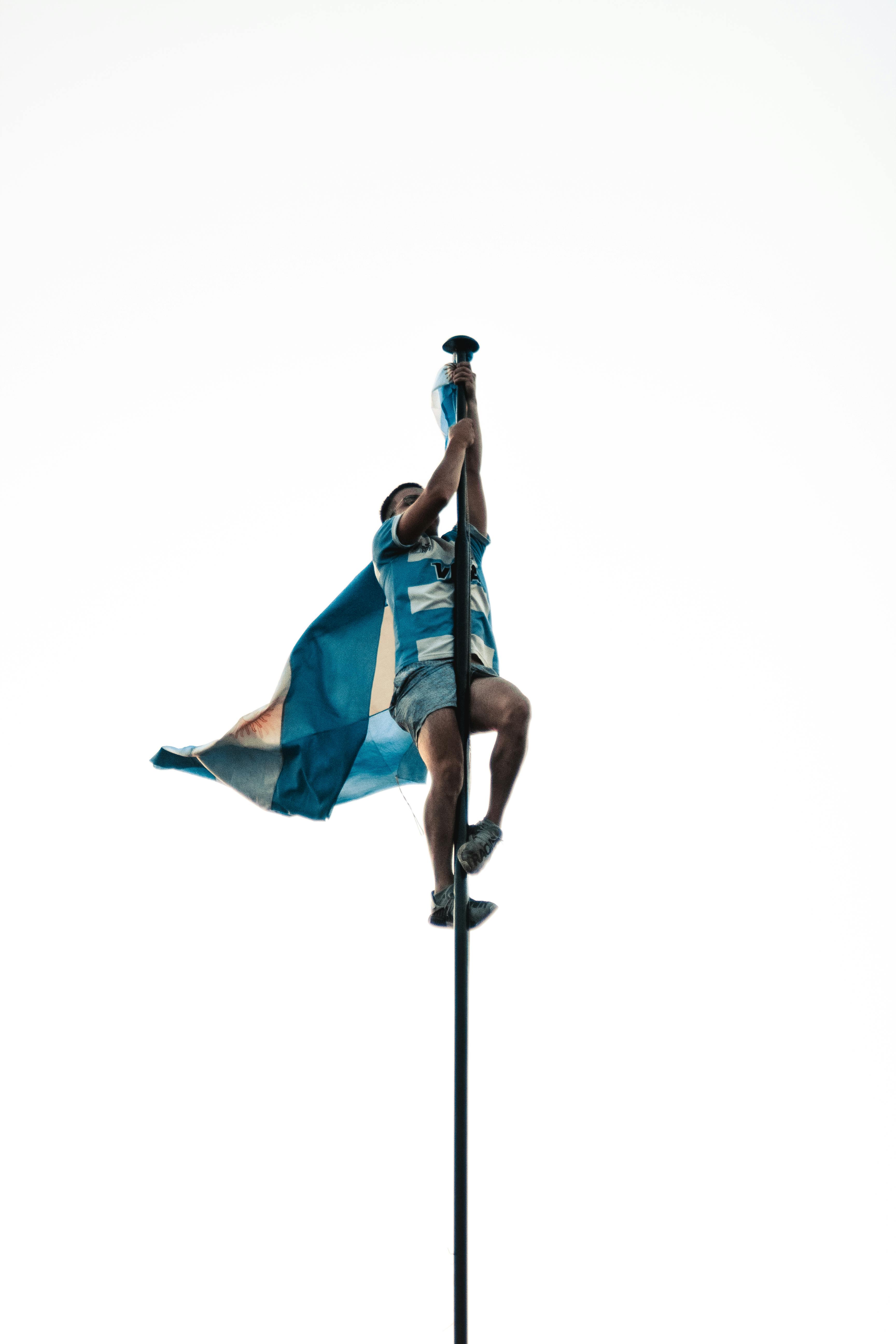 Man Climbing Flagpole Holding Flag Celebrating · Free Stock Photo