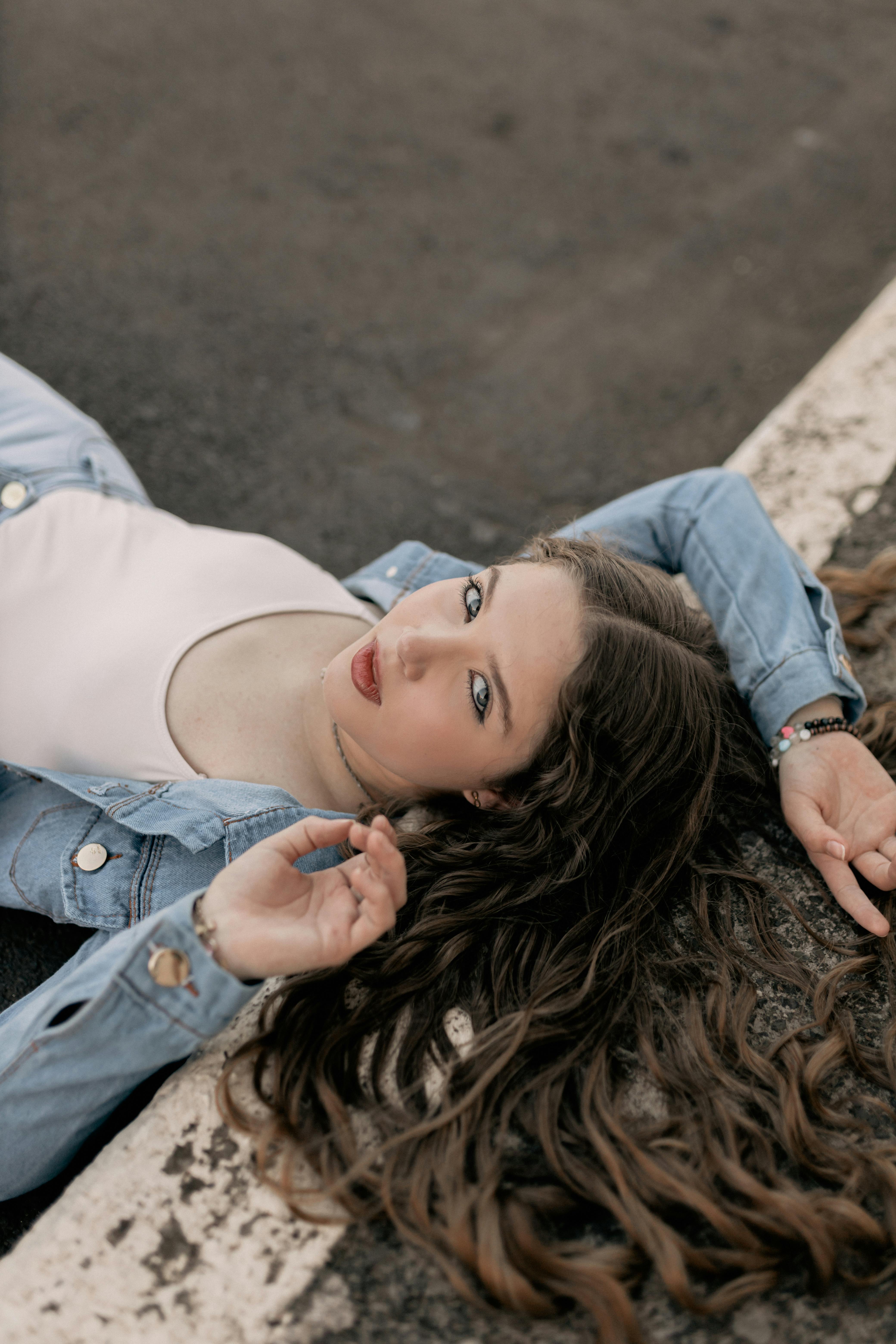 Young woman in denim jacket lying outdoors · Free Stock Photo