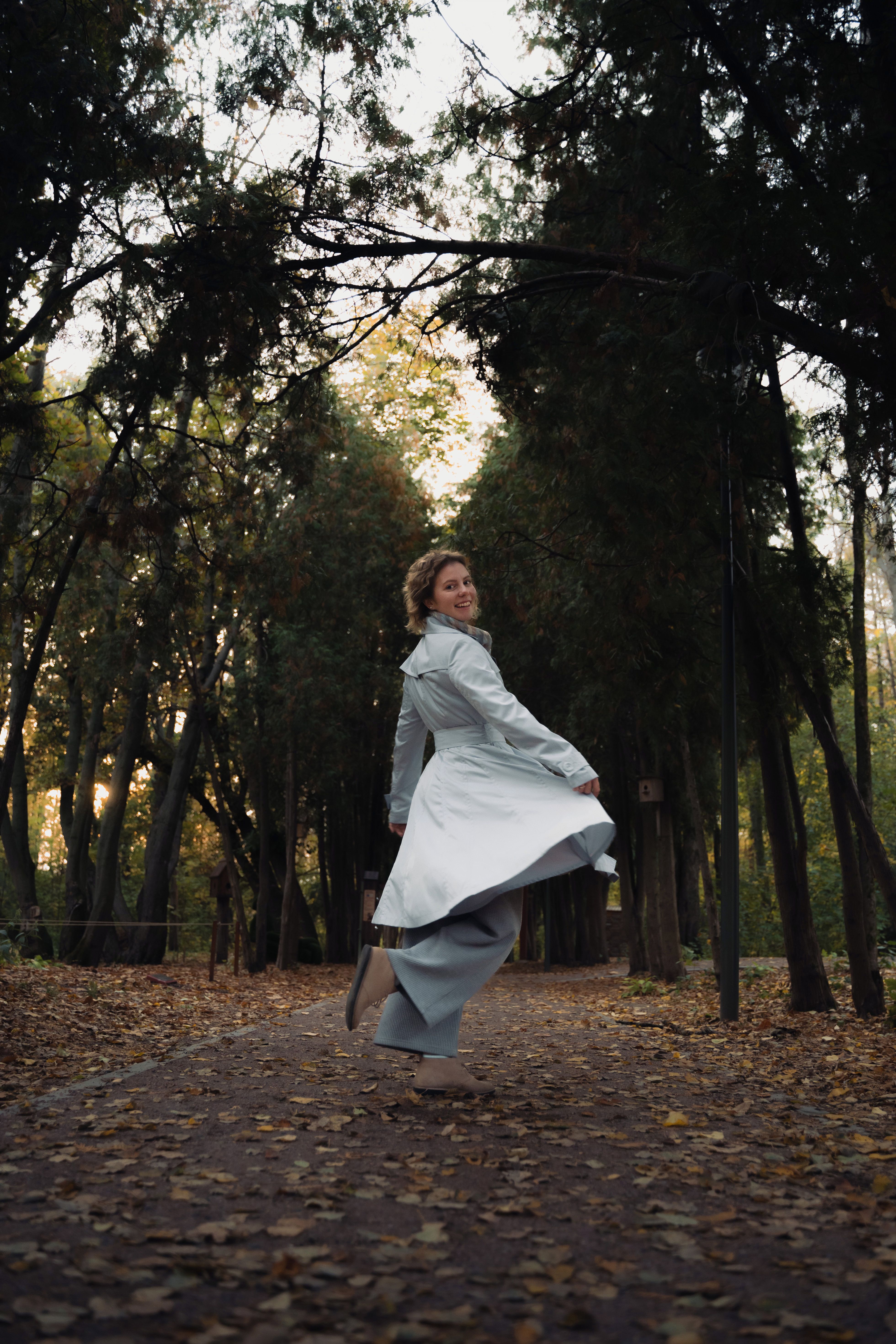 Woman Twirling in Autumn Forest Pathway · Free Stock Photo