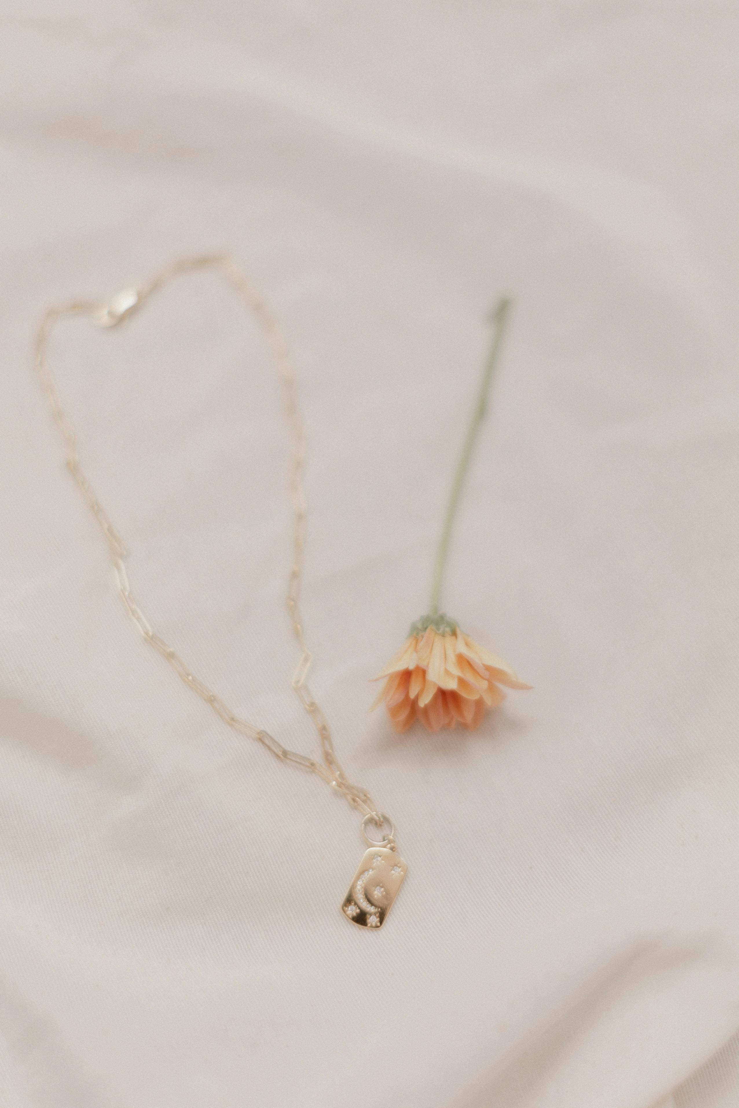 Delicate Gold Chain with Drooping Flower on Fabric · Free Stock Photo