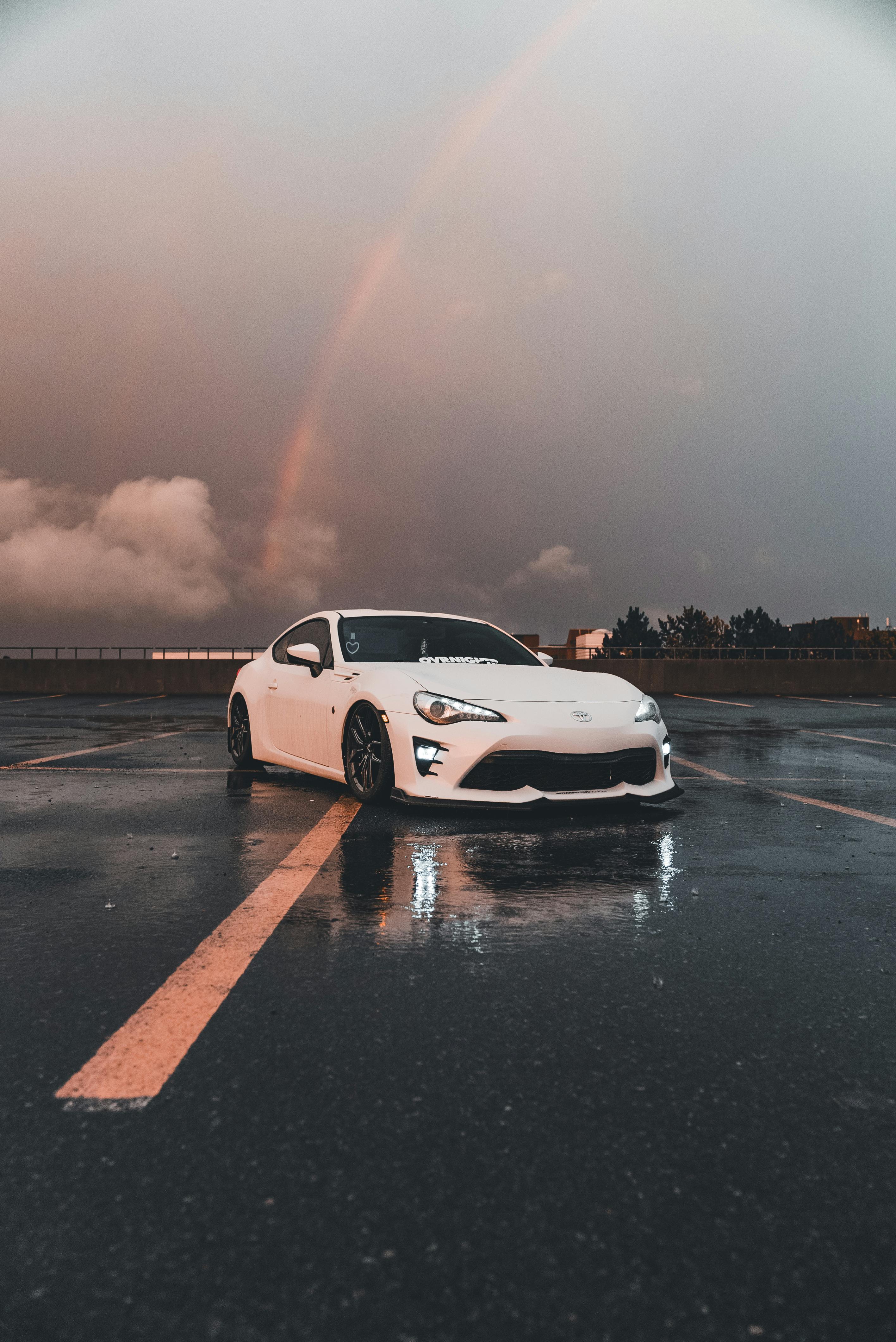 Sleek White Sports Car in Rain with Rainbow · Free Stock Photo