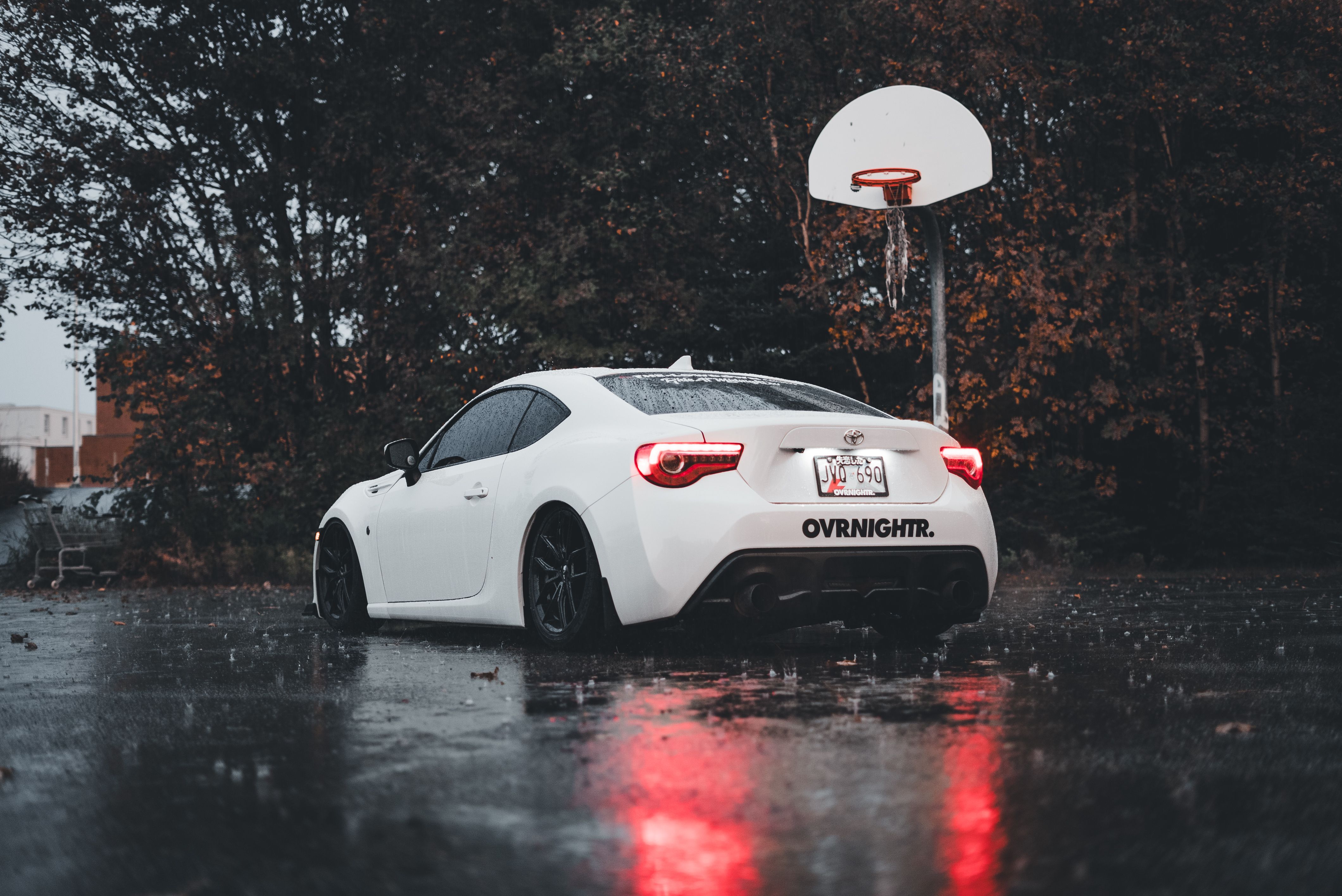 White Sports Car in Rainy Outdoor Basketball Court · Free Stock Photo