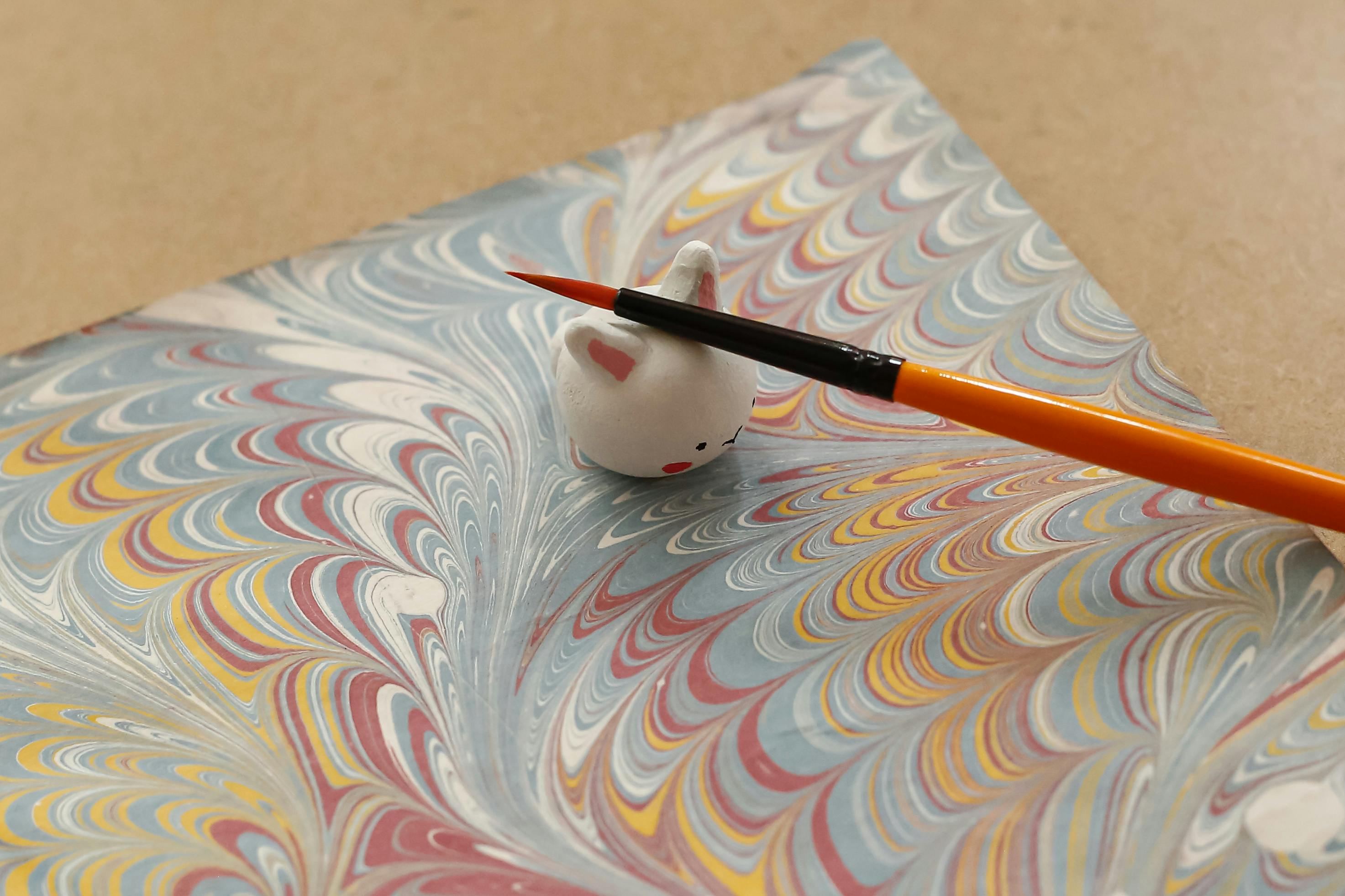 Colorful Marbled Paper with Paintbrush and Cat Figurine · Free Stock Photo