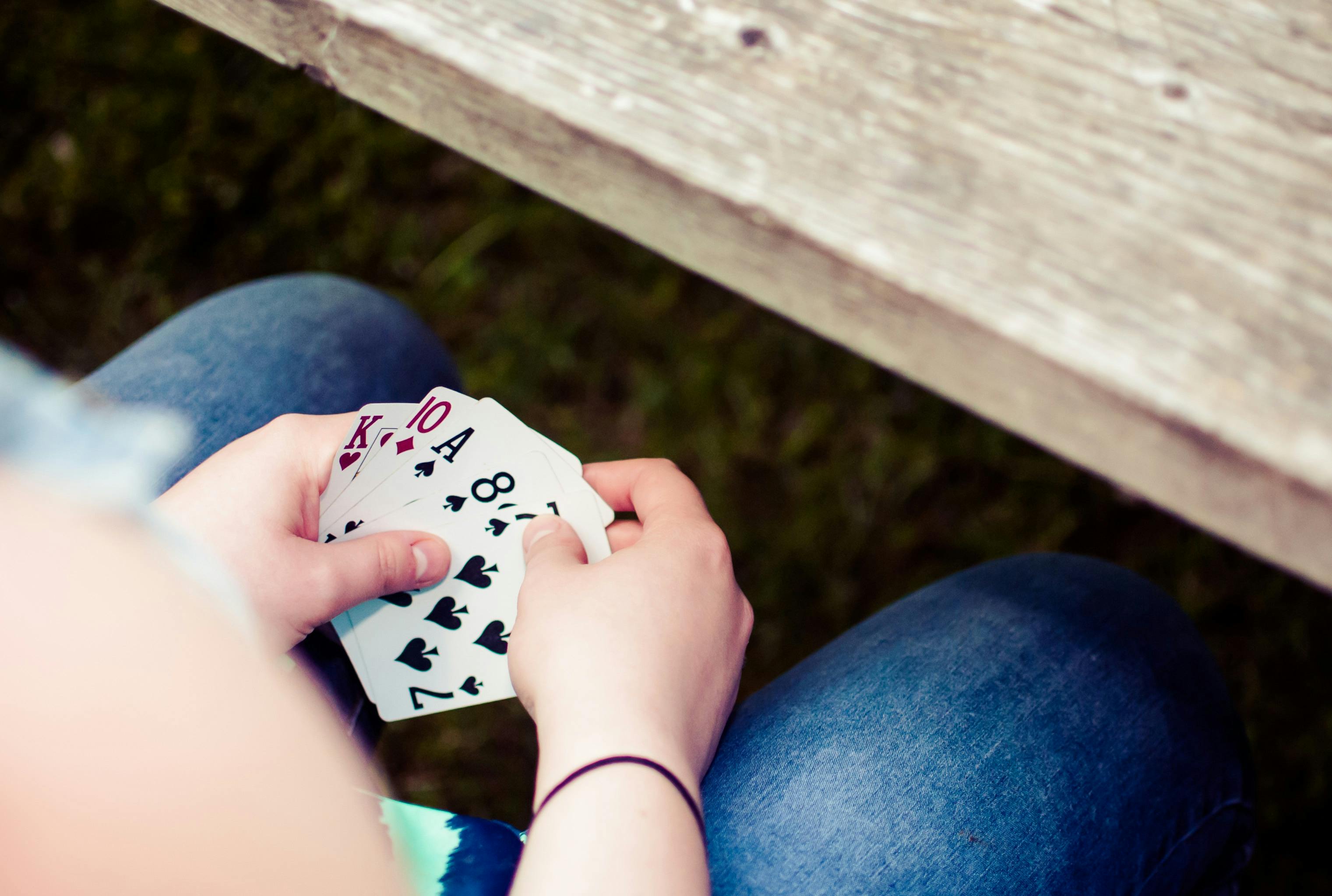 Close-up of Hands Holding Playing Cards Outdoors · Free Stock Photo