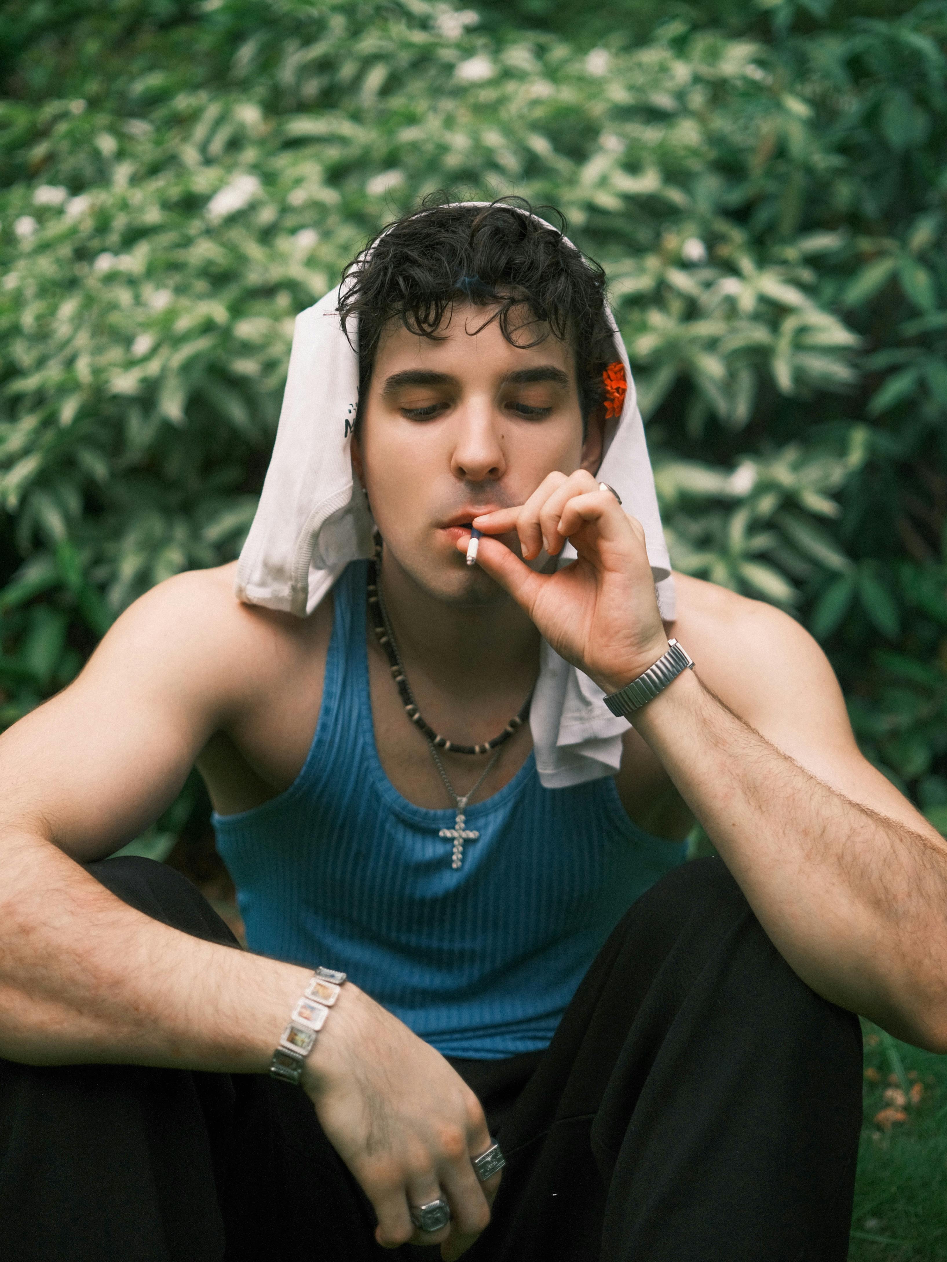 Young Man Relaxing Outdoors with Cigarette · Free Stock Photo