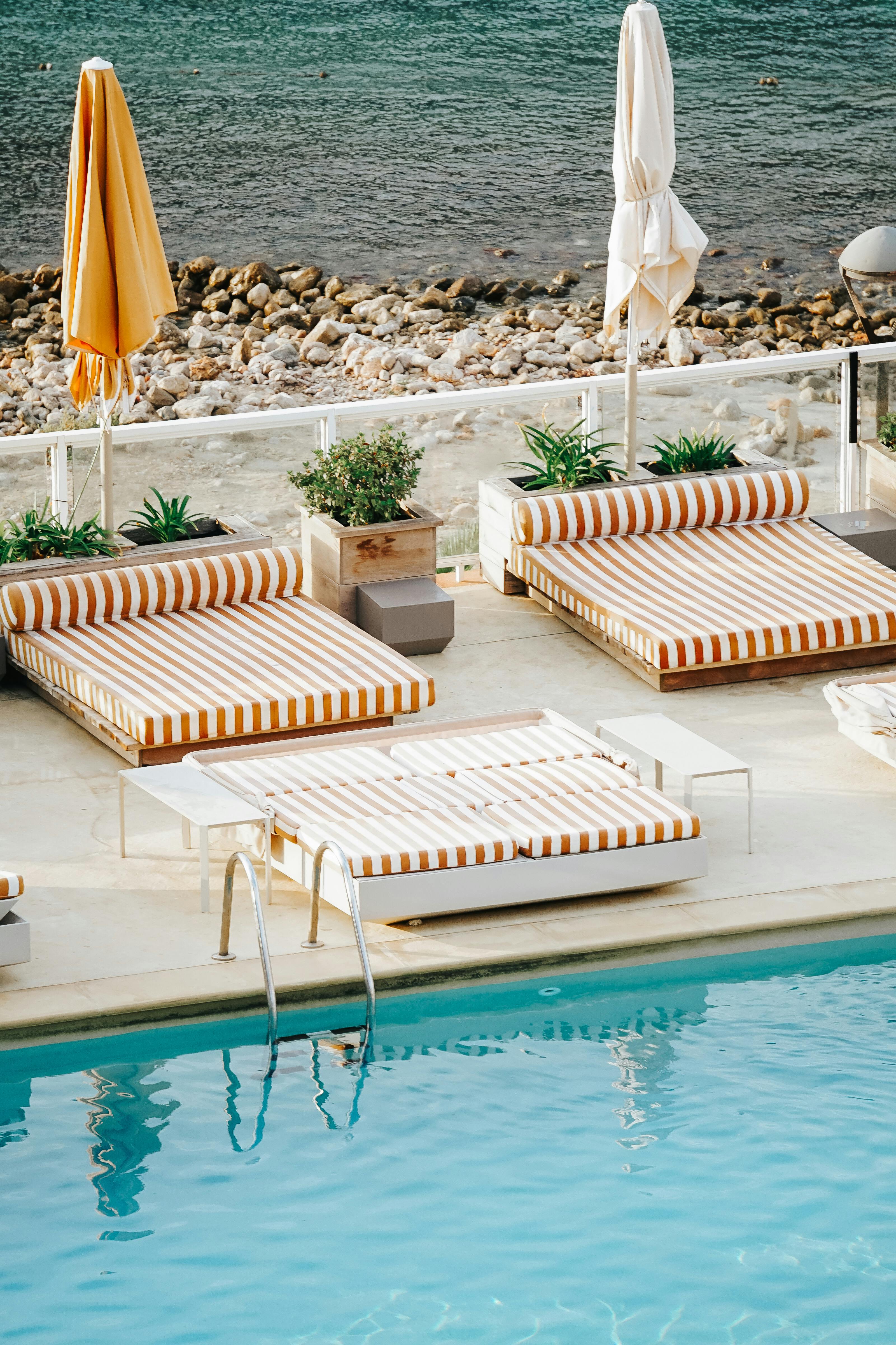 Luxurious Seaside Pool with Striped Loungers · Free Stock Photo