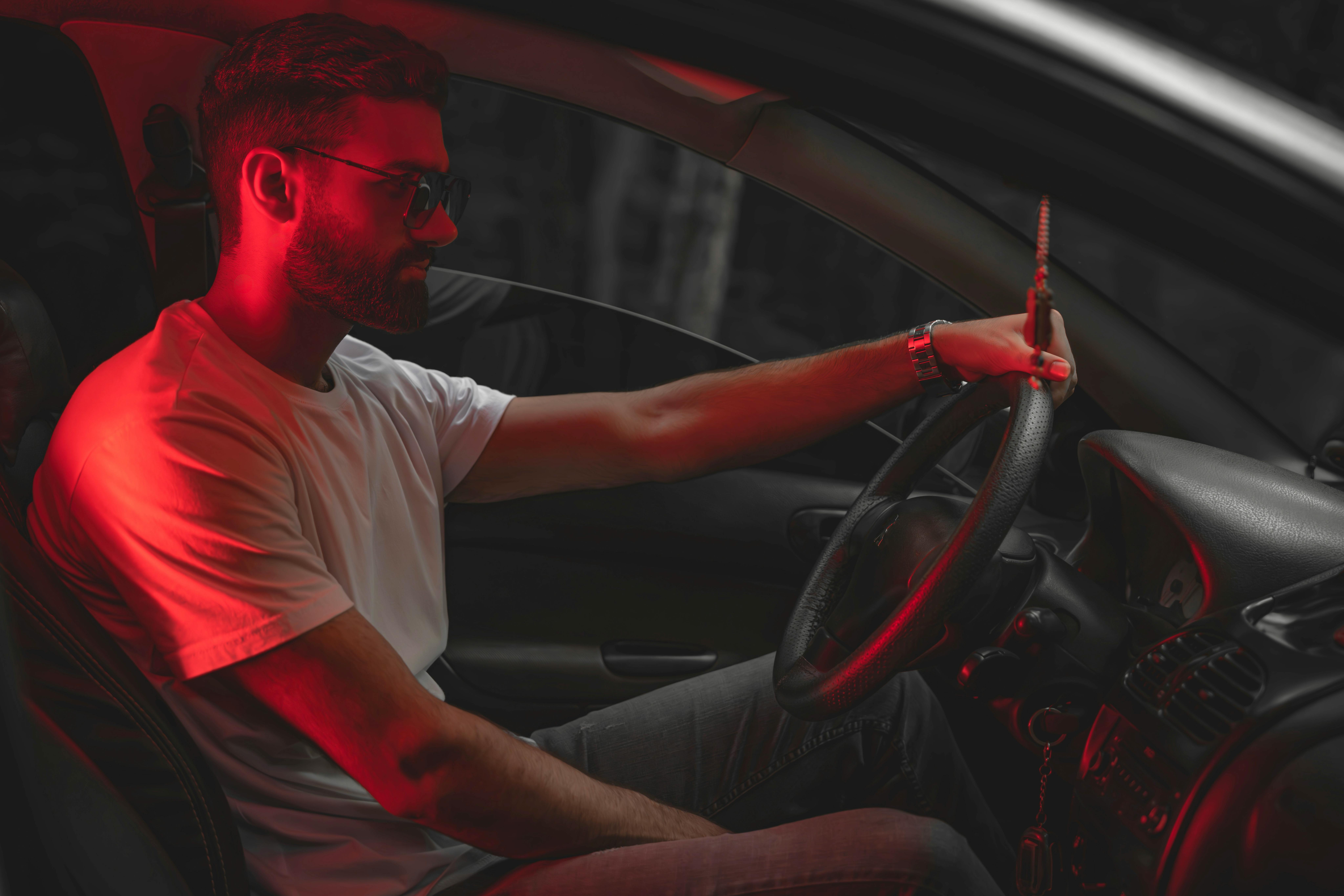 Young man driving at night with red lighting · Free Stock Photo