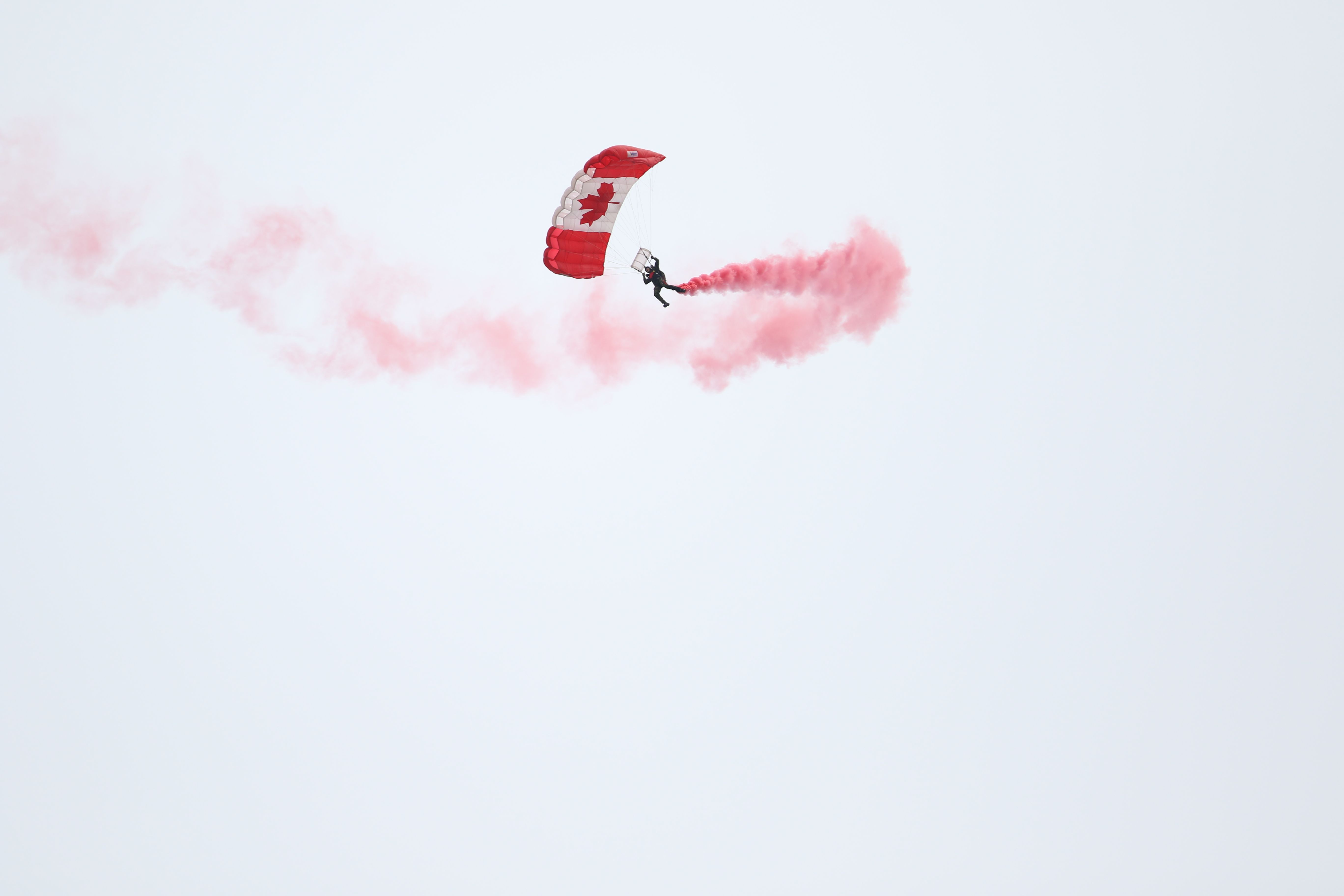 Paraglider with Canadian Flag and Smoke Trail in Sky · Free Stock Photo