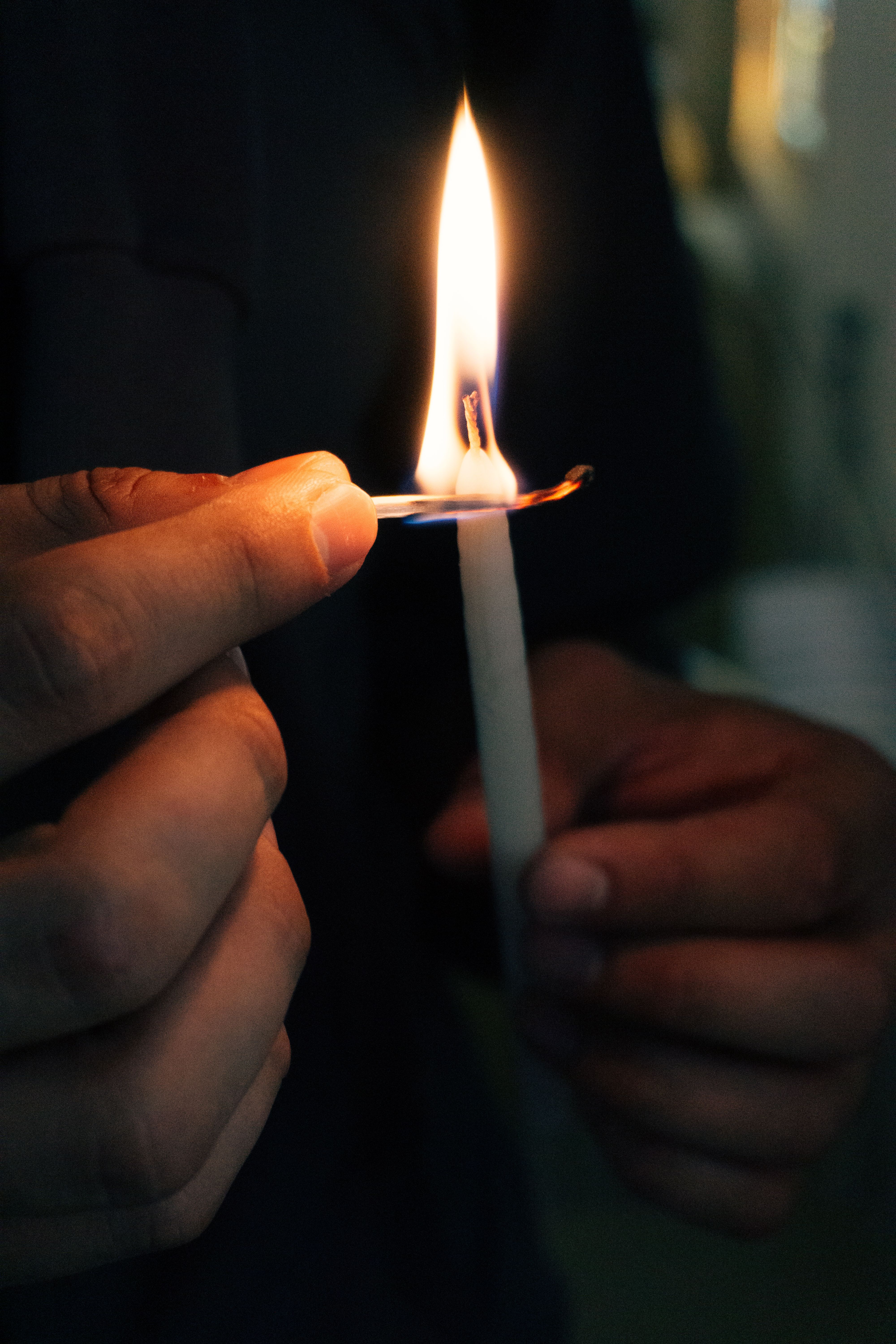 Person lighting a candle in low light ambiance · Free Stock Photo