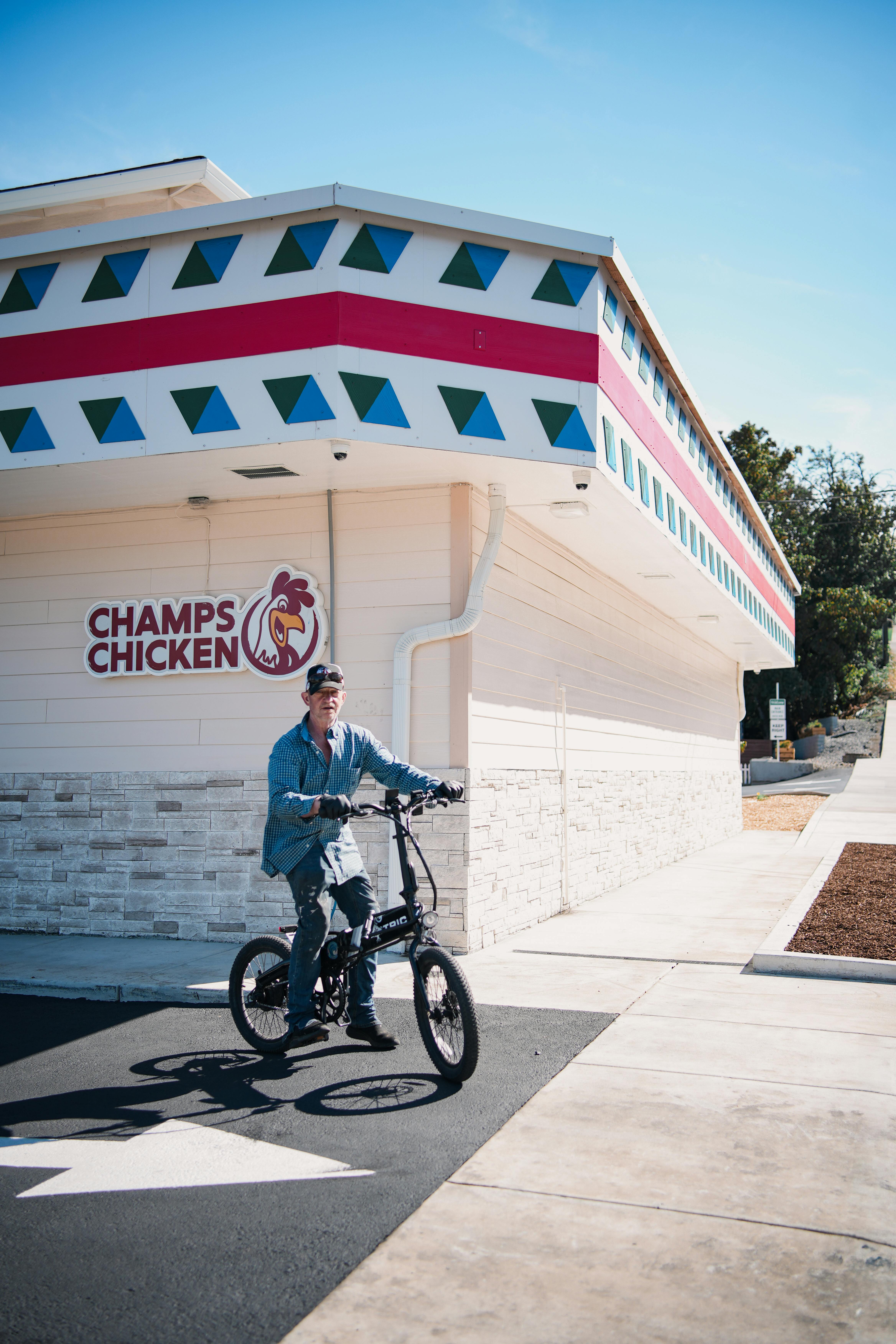 Cyclist in Front of Champs Chicken Restaurant · Free Stock Photo