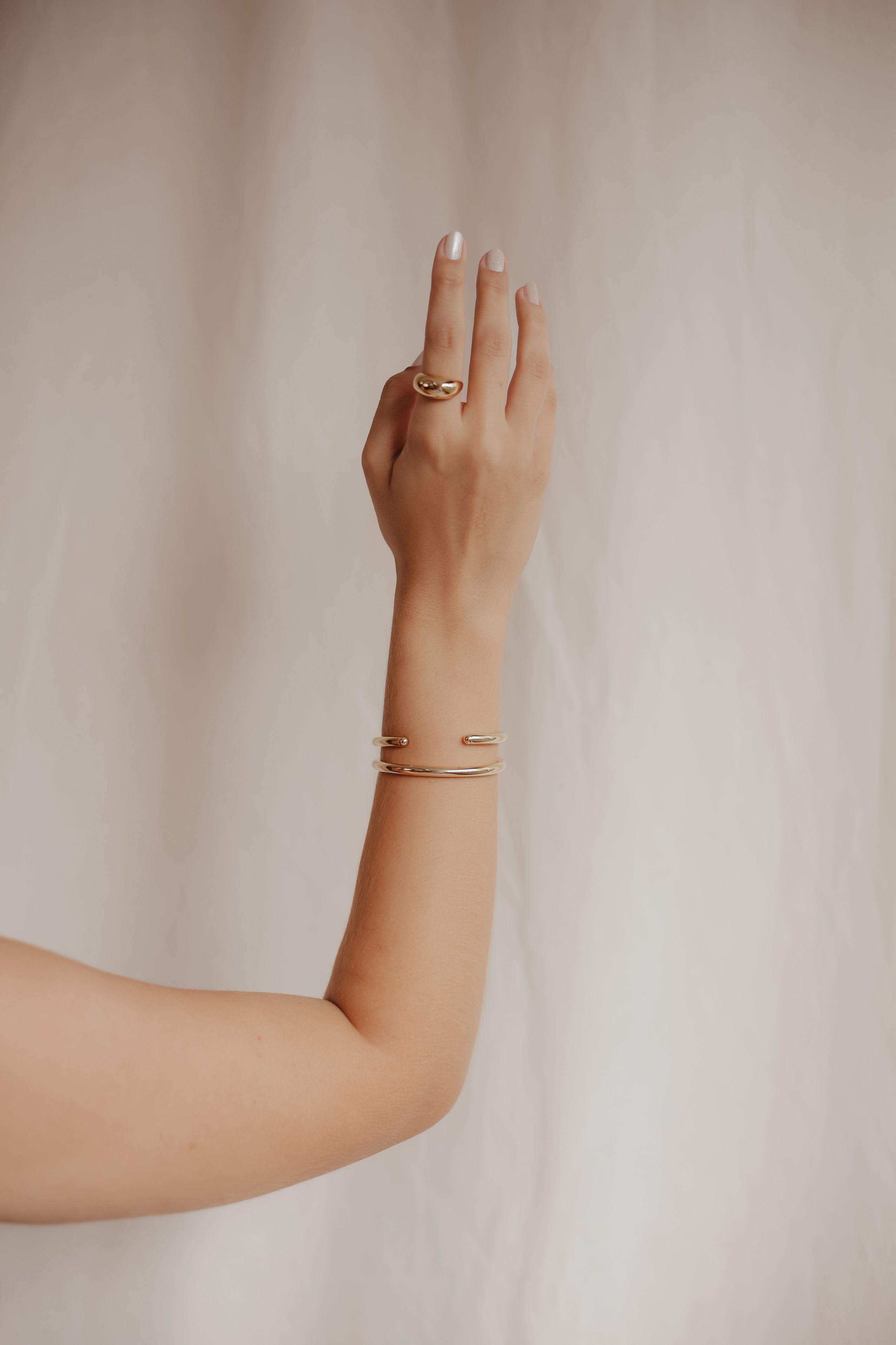Elegant Arm with Gold Jewelry Raised Against Neutral Backdrop · Free ...
