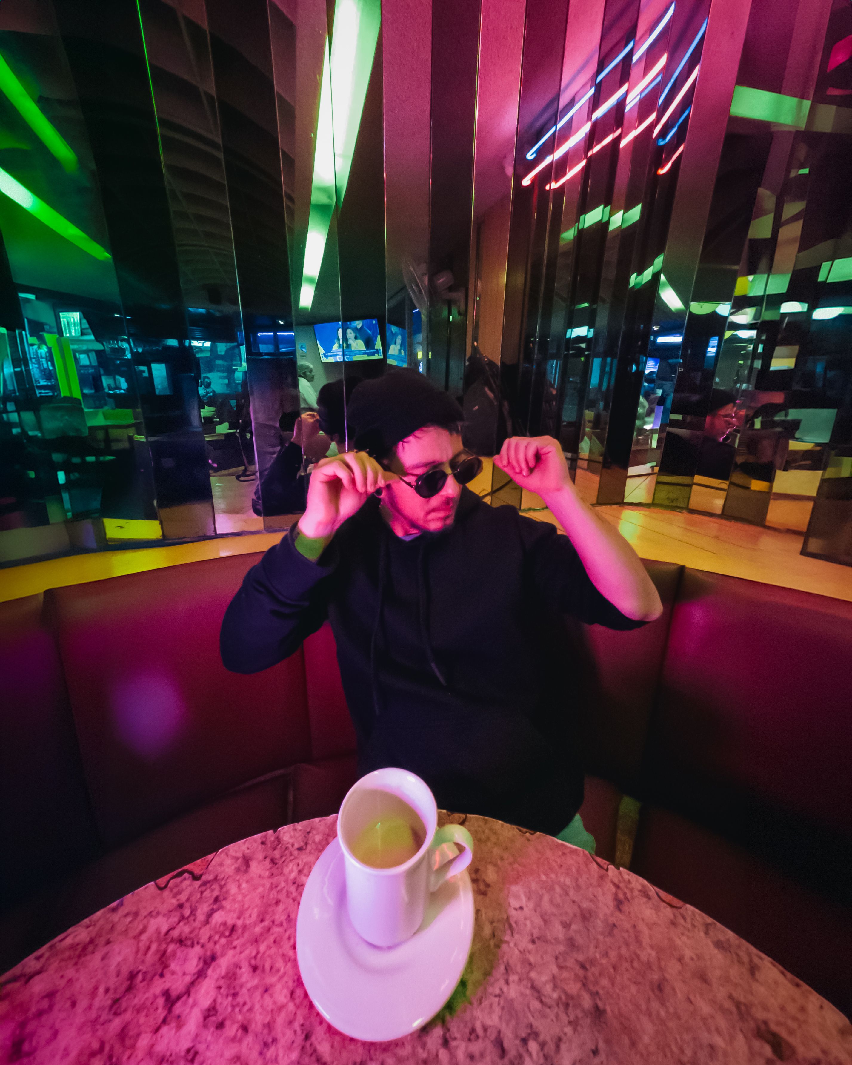 Stylish man in vibrant cafe setting with drink · Free Stock Photo