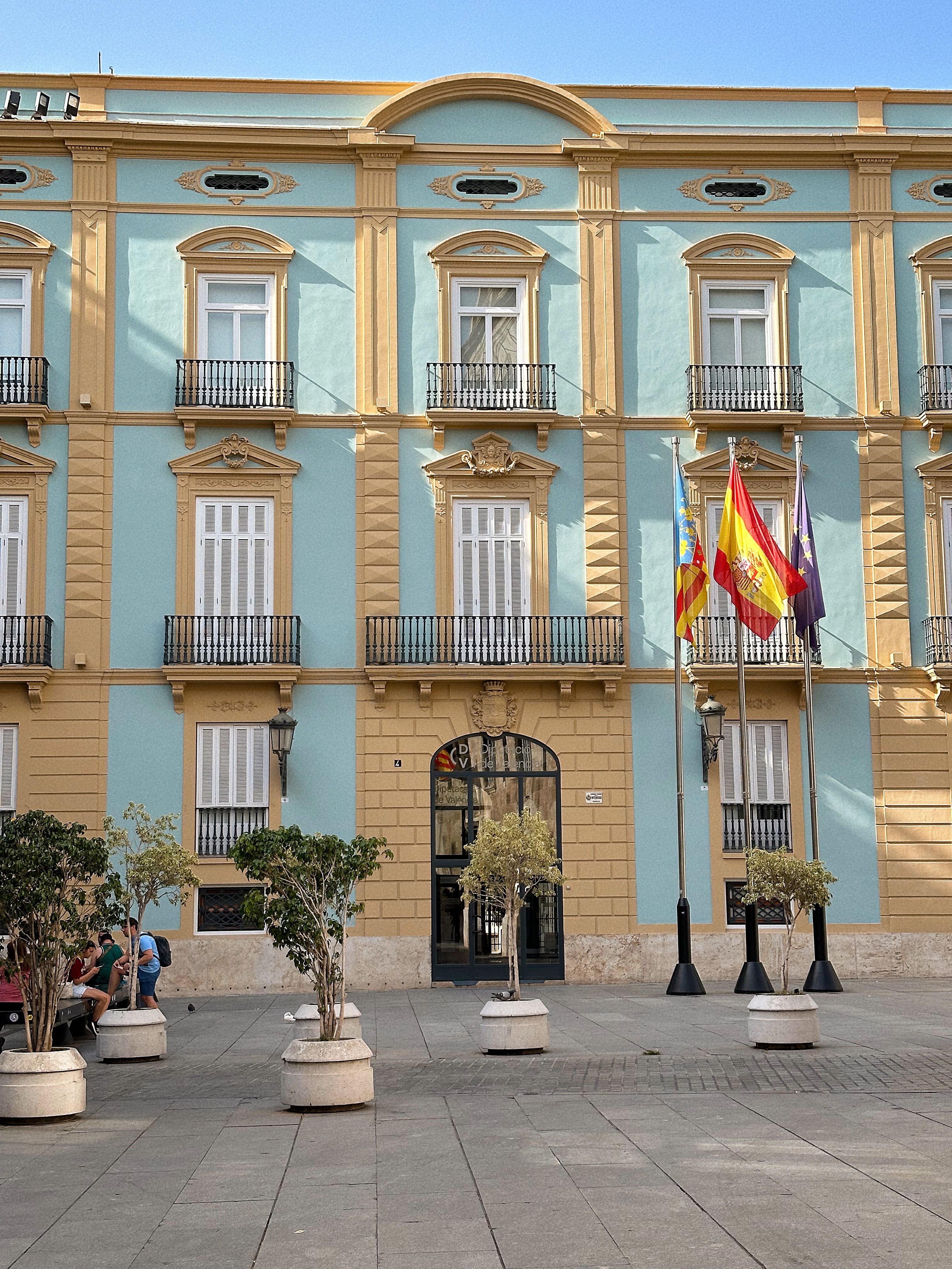 Elegant Spanish Building with Vibrant Flags · Free Stock Photo